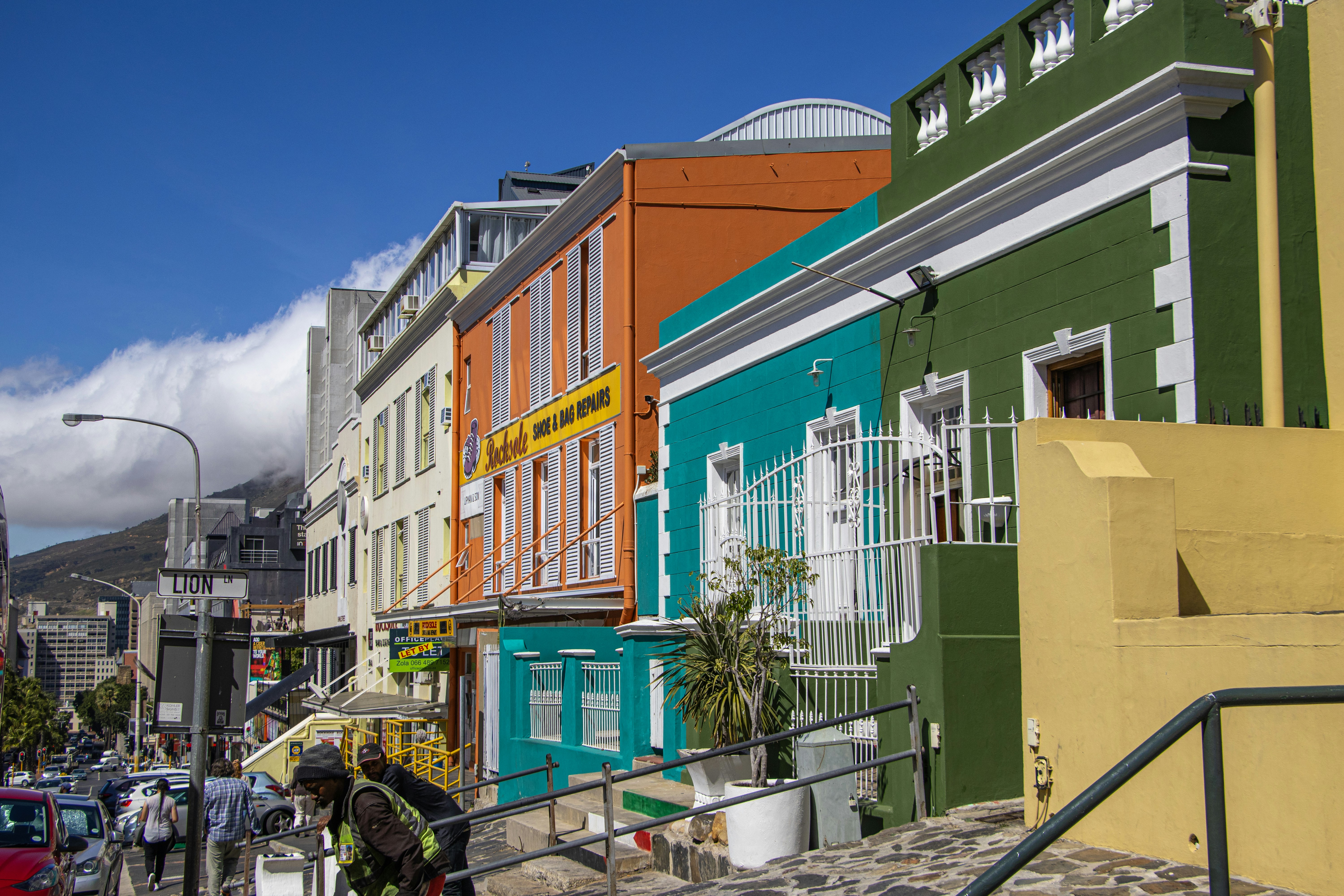 Candy-Hued Facades: A Sunlit Row of Shops on a Sloped Coastal Street