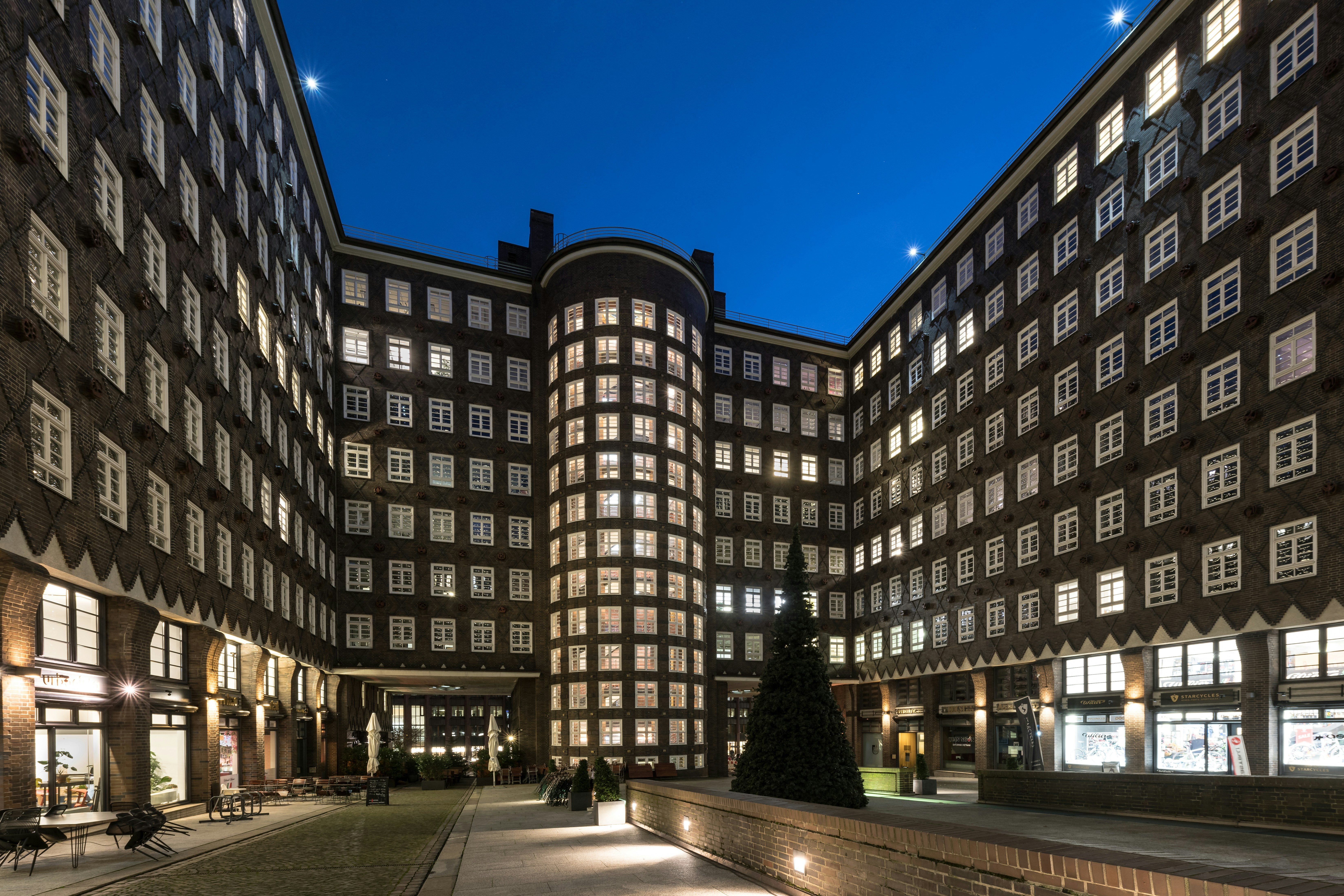 Circular Glass Atrium at Night: Warm Light in a Brick Campus Courtyard