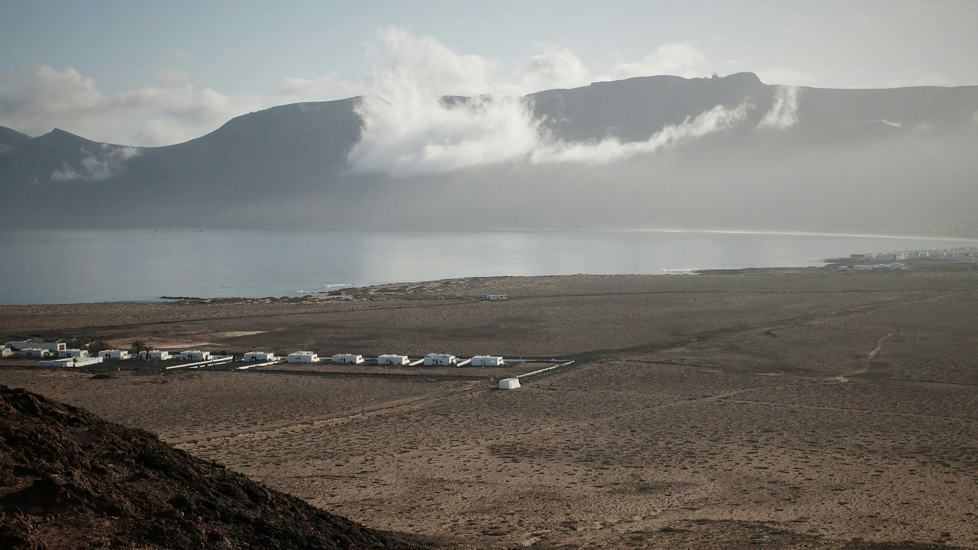 Quiet shoreline encampment beneath a brooding mountain range