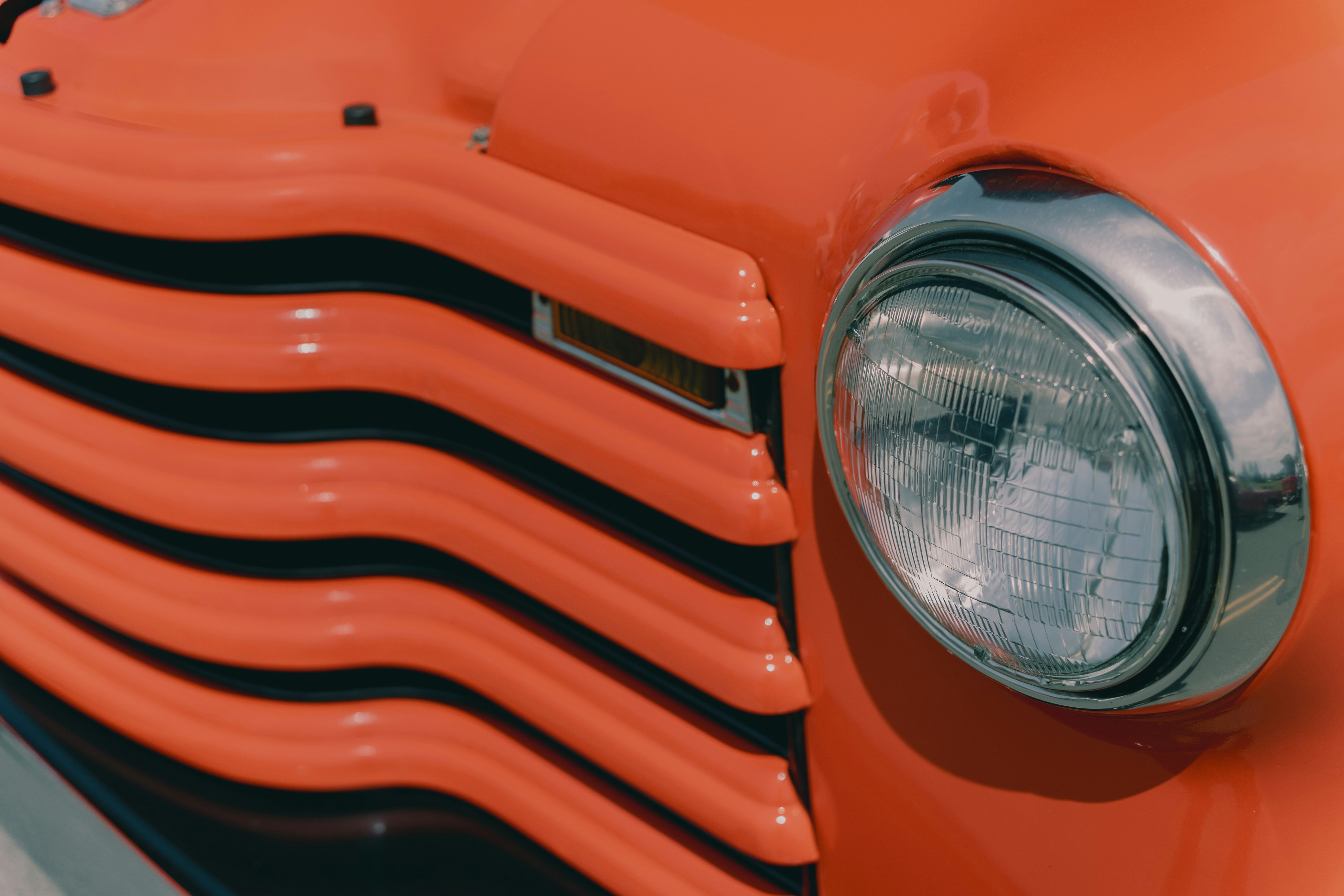 Curved Orange Chrome: The Grille and Headlight of a Classic Truck