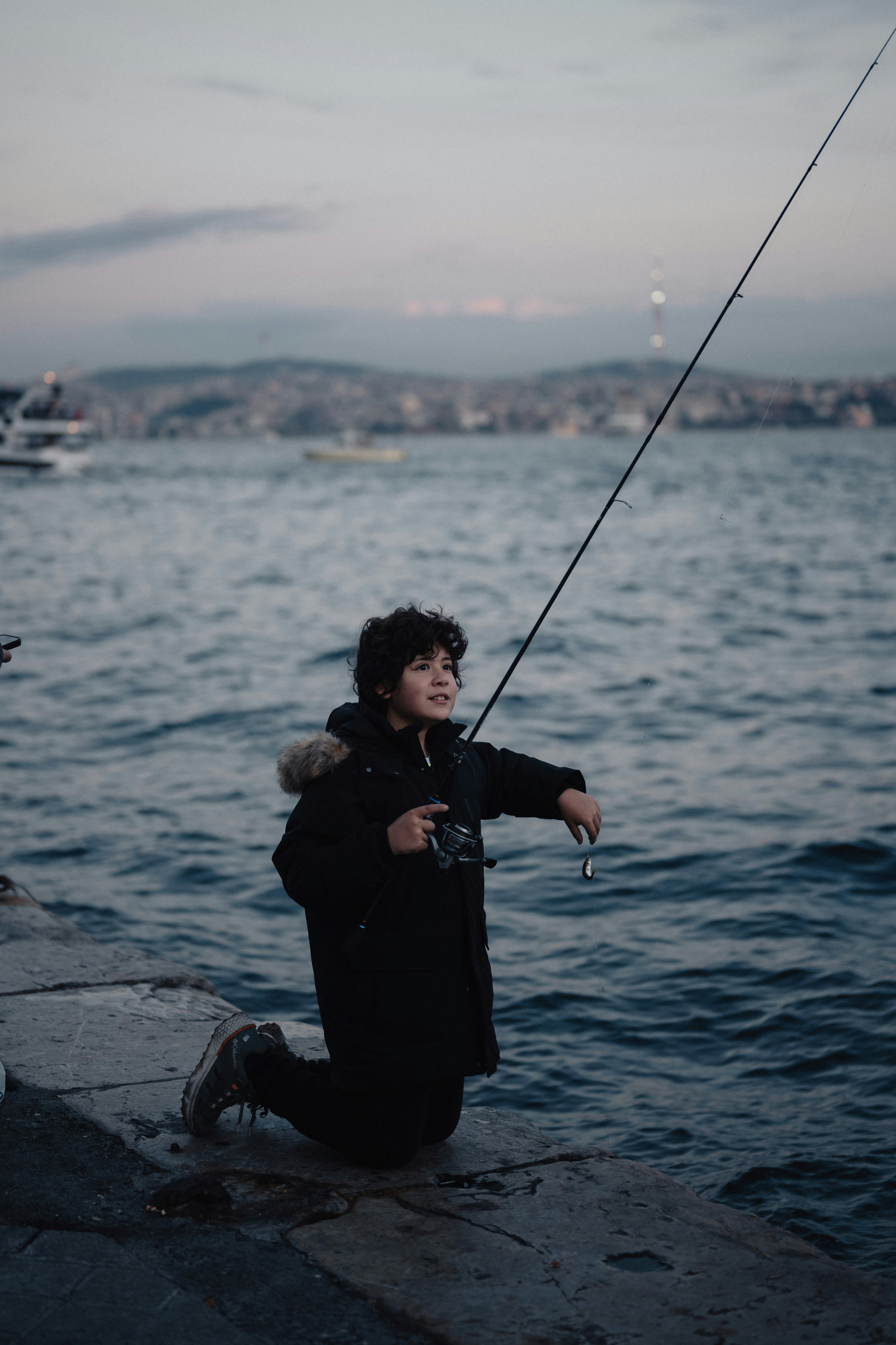 A man sitting on the edge of a pier while fishing