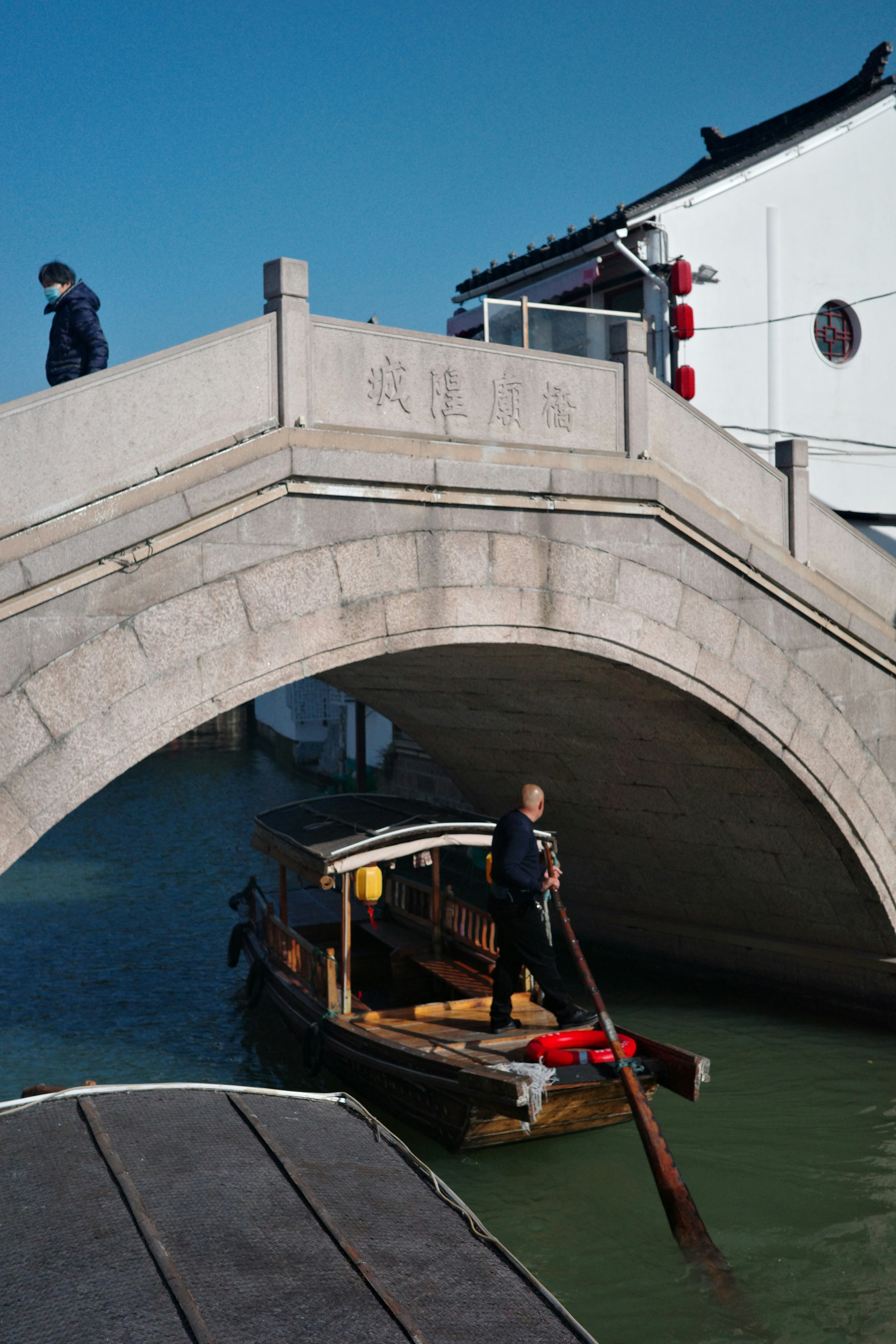 Stone-Arch Crossing: A Boatman Steers Through a Quiet Canal