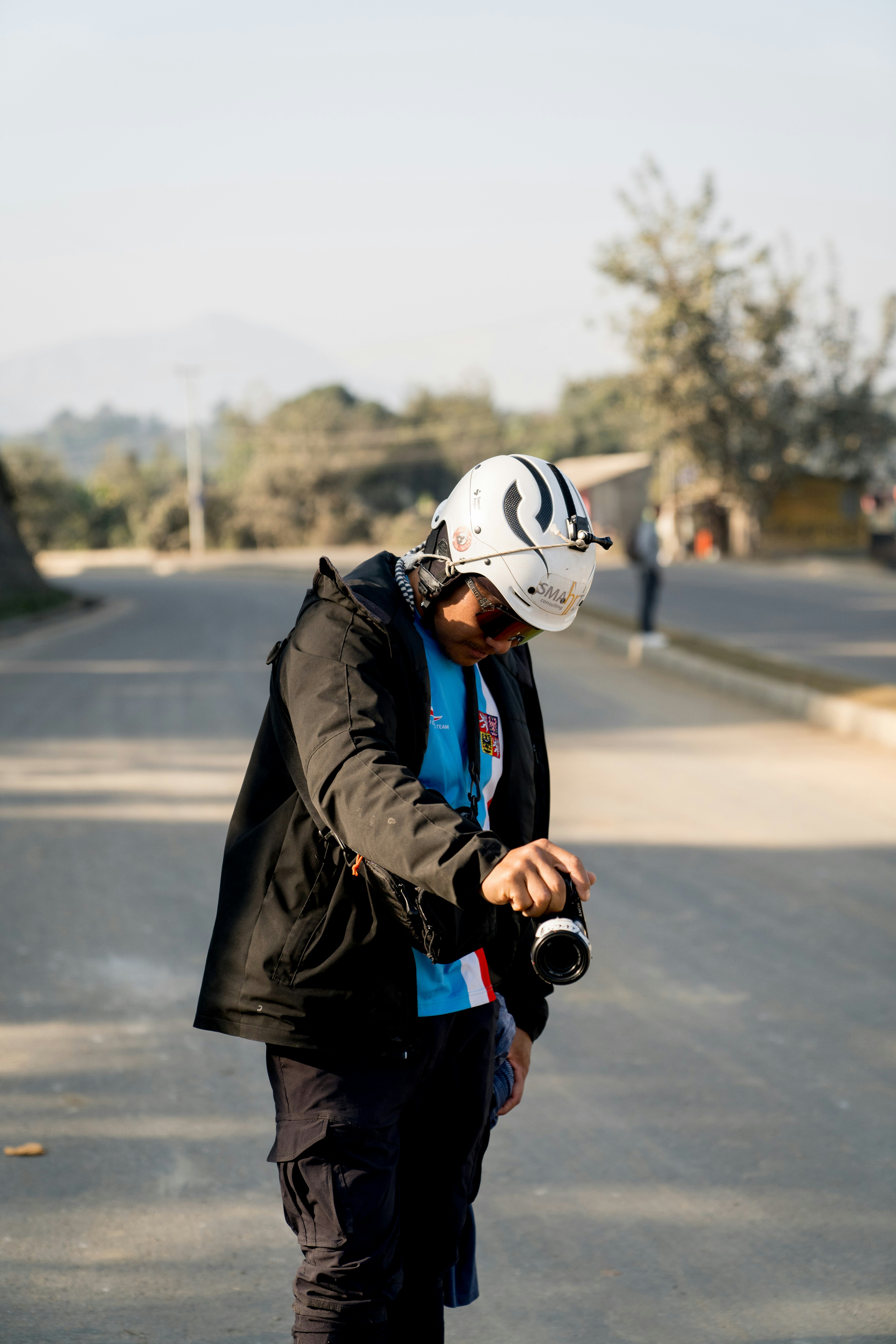 Helmeted Street Photographer Capturing a Quiet Road Moment
