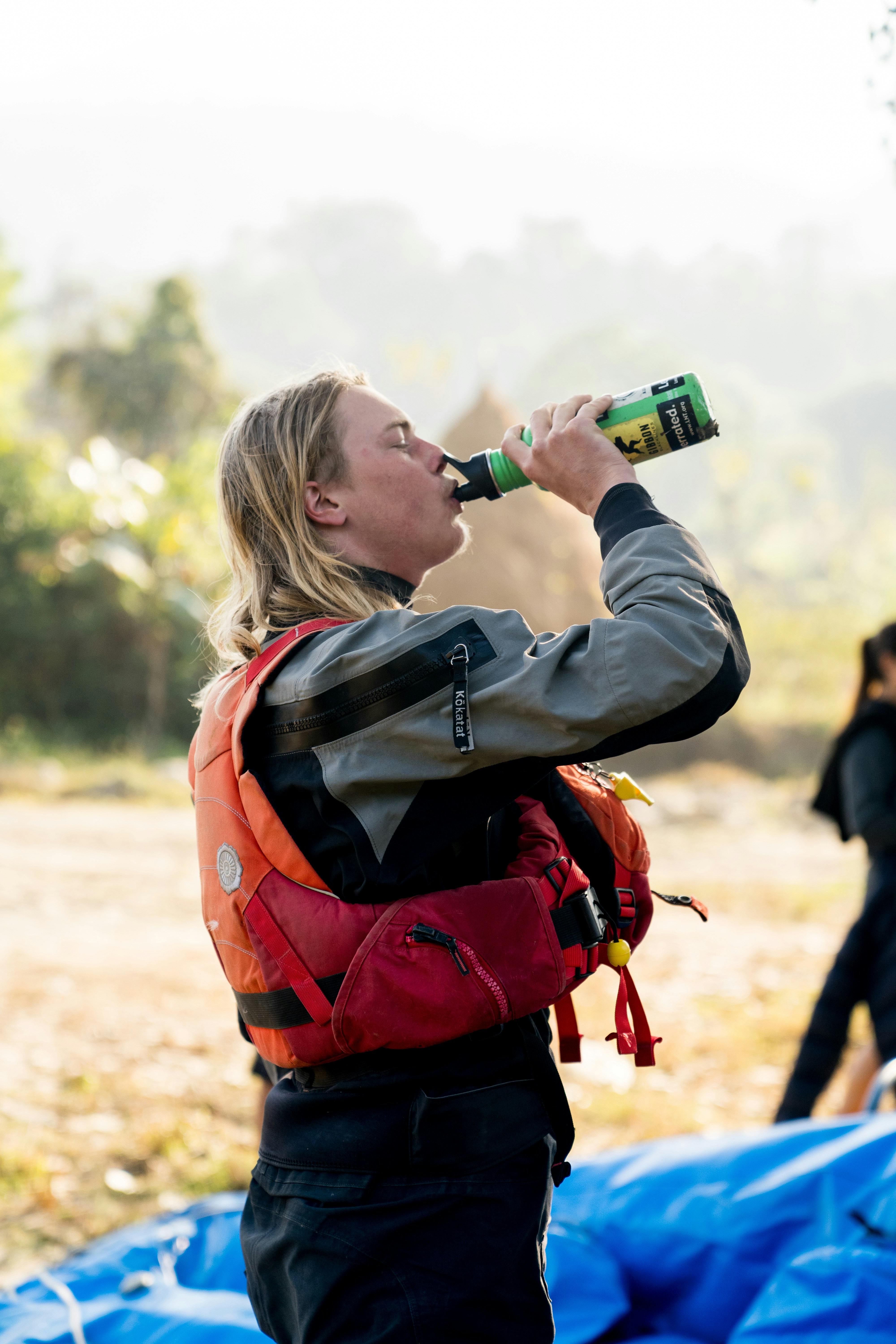 Hydration Break by the Riverside: Orange Vest and a Green Bottle