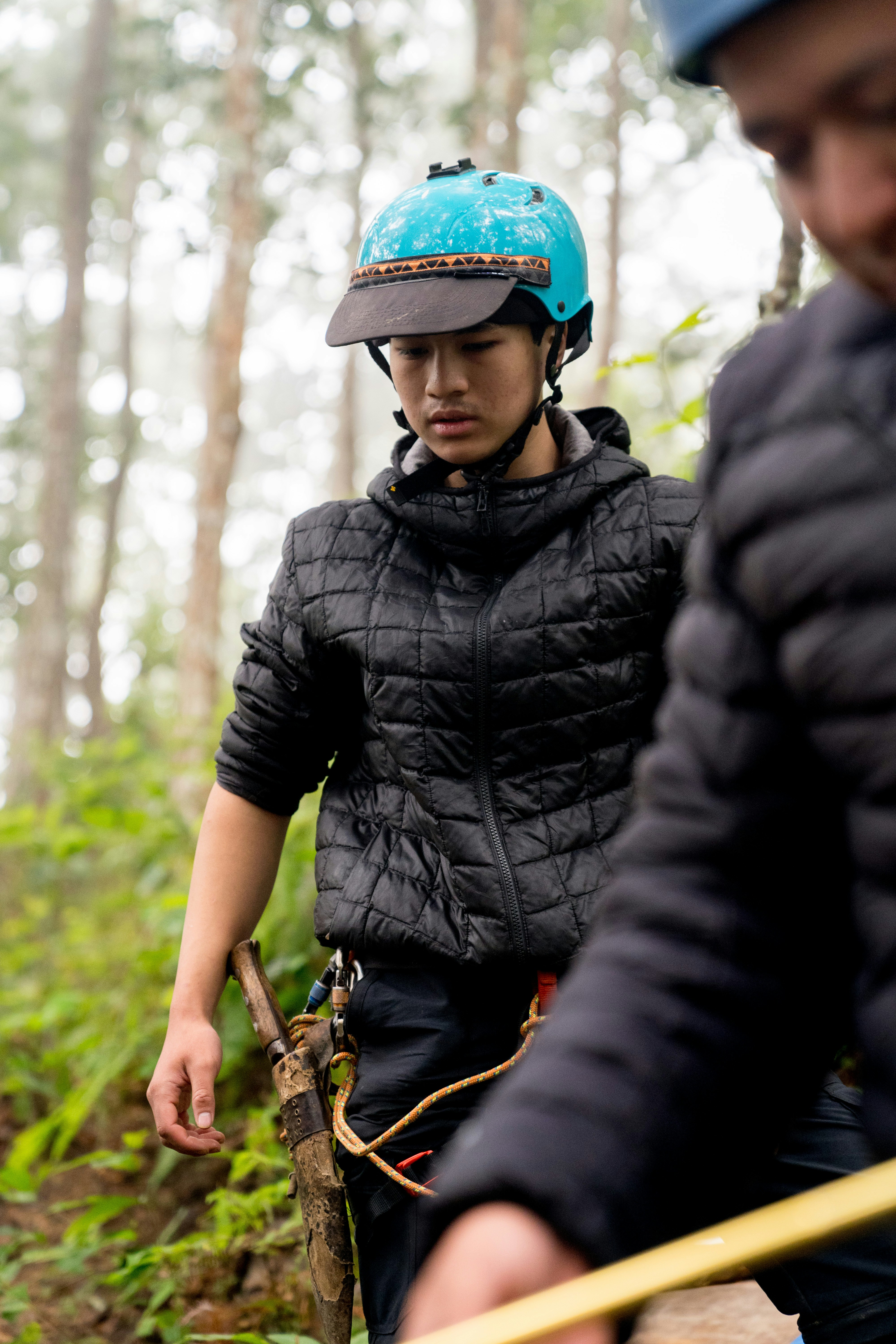 Helmeted Focus: A Youth Adventurer Reaches for a Trek in the Woods