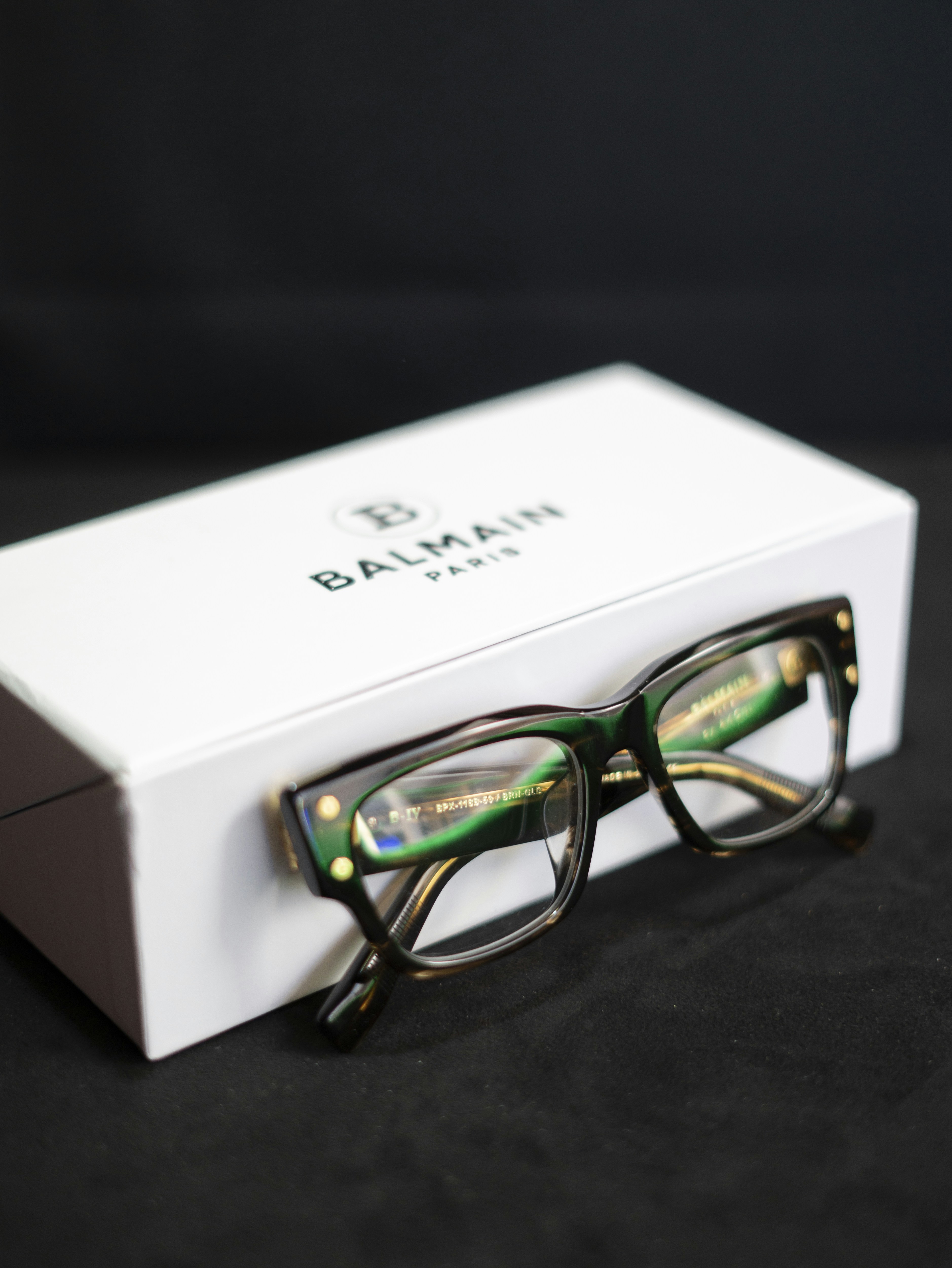 Silent Focus: Glasses Resting beside a Balmain Box