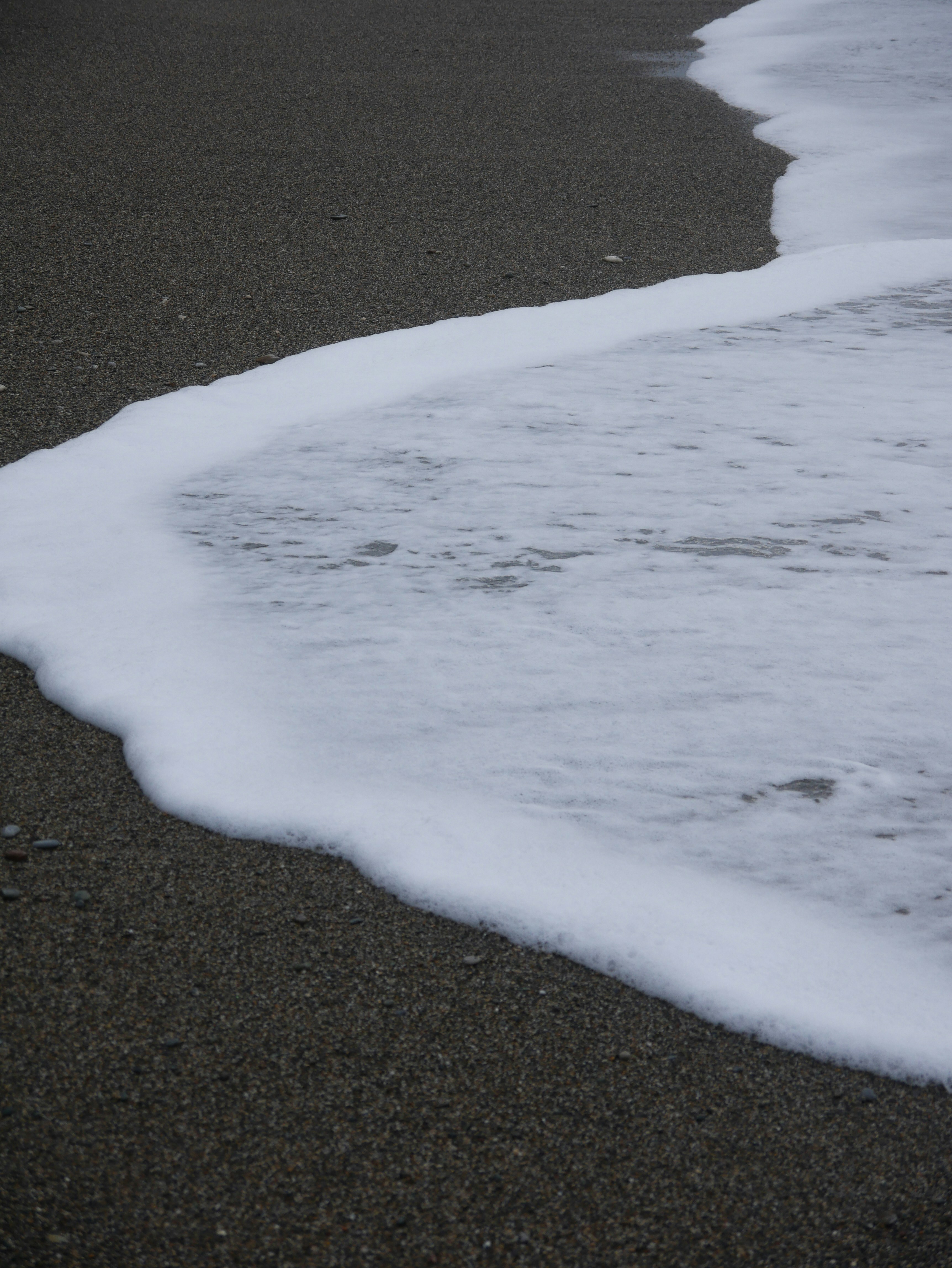 Foam Ribbon Tracing a Pebbled Shore at Quiet Light