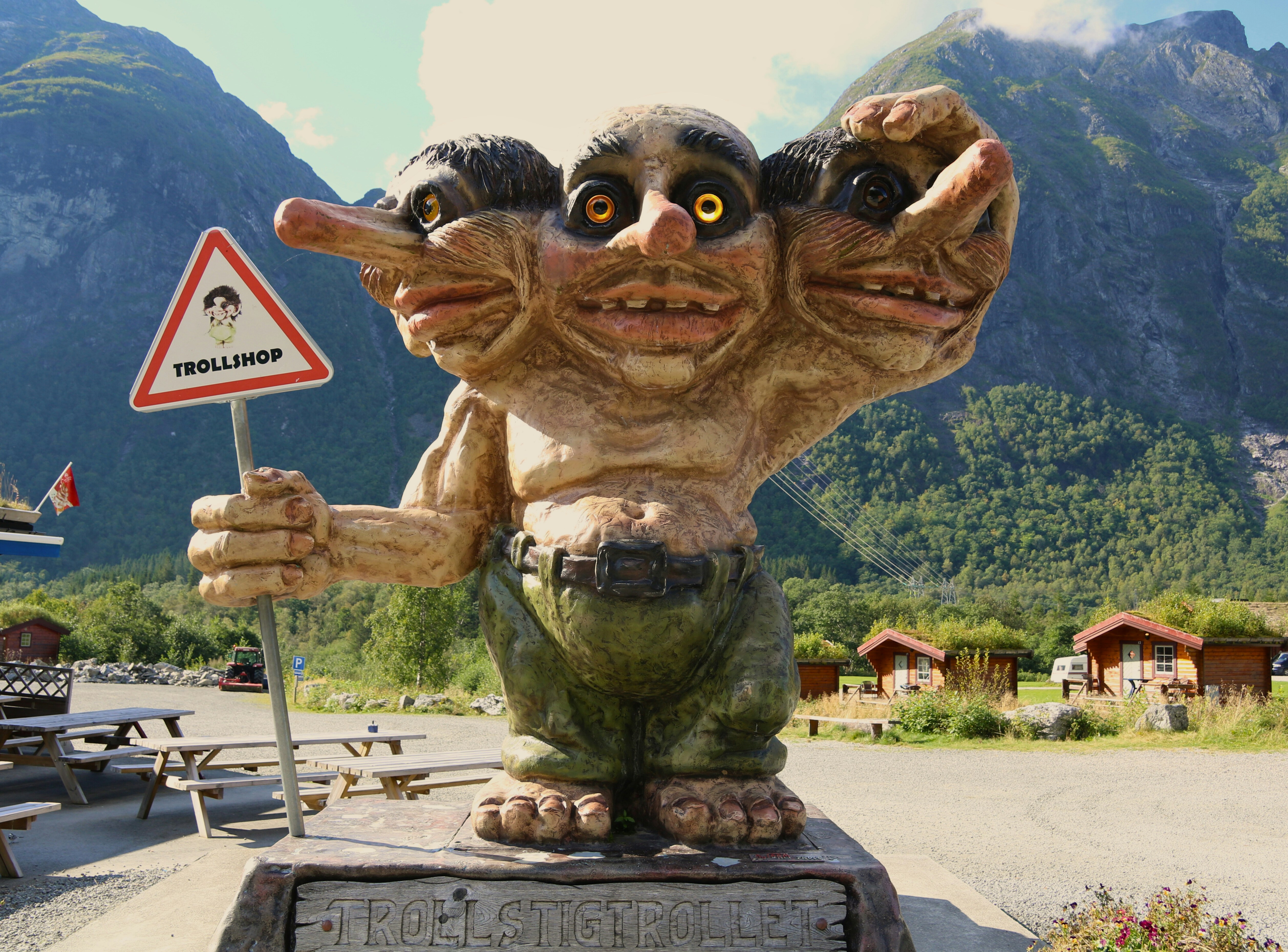 A statue of a troll holding a sign in front of a mountain photo – Free ...