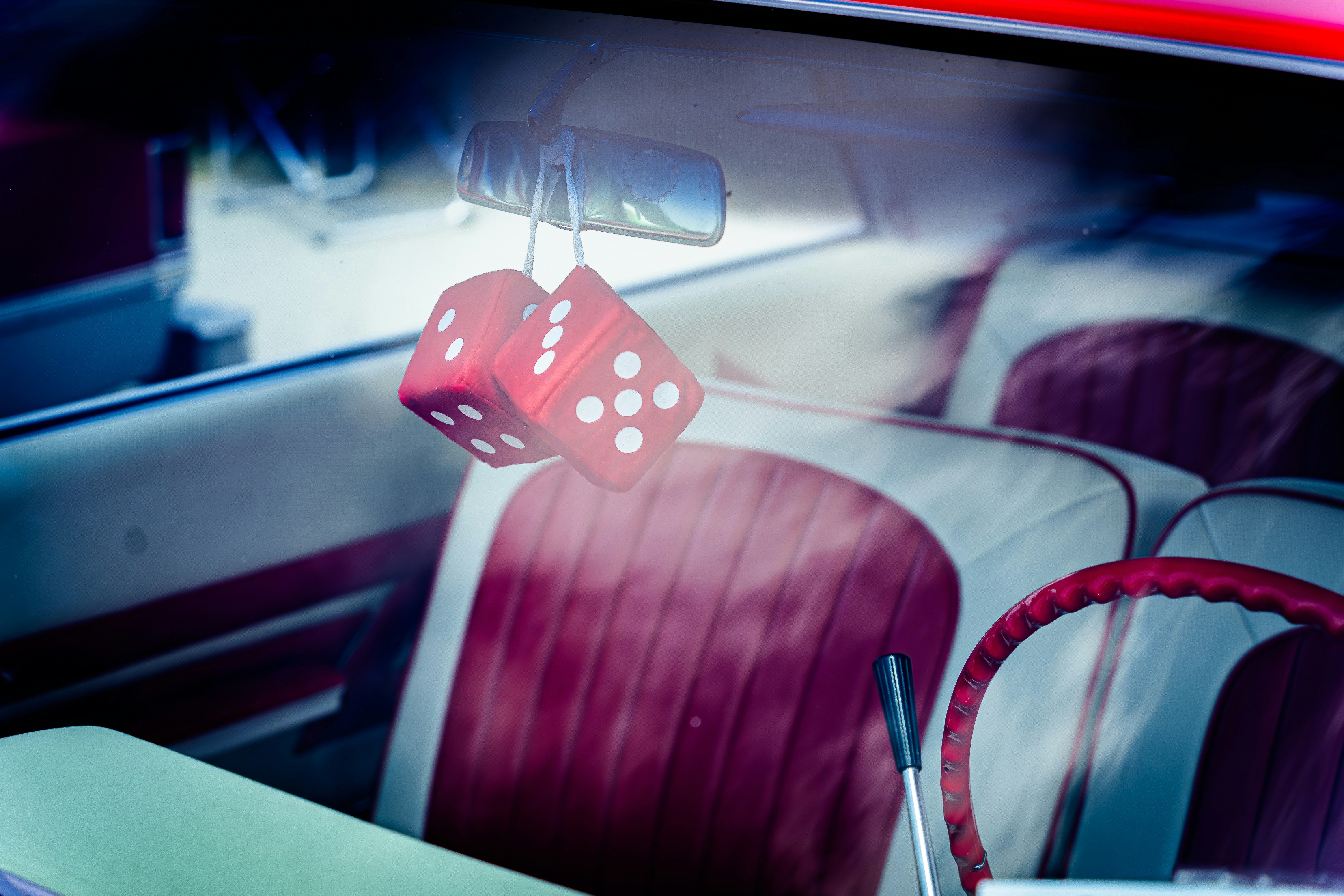 A red car with a pair of dice hanging from it's side window photo ...