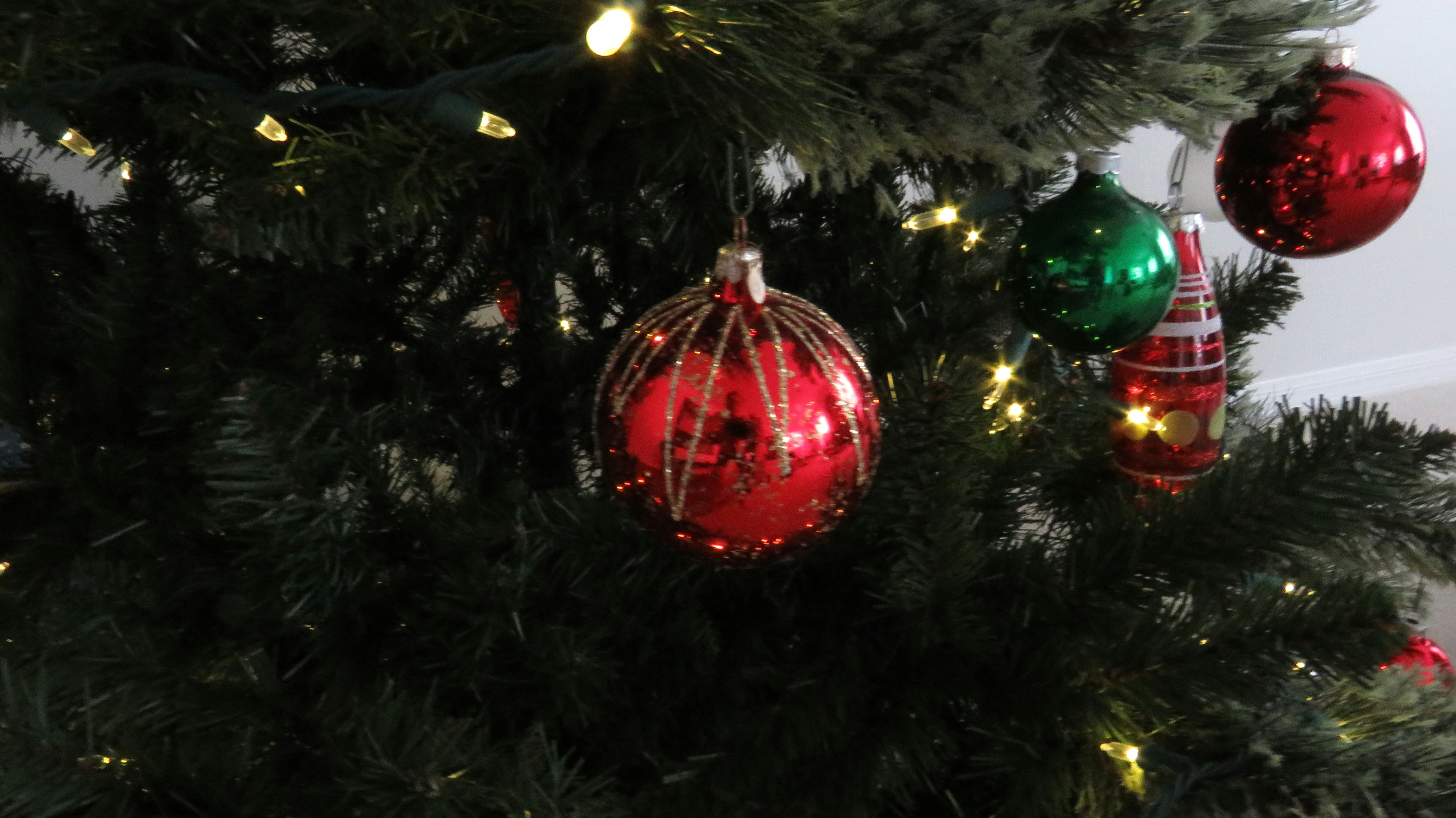 Crimson Bauble Amid Soft Fairy-Lights on a Christmas Tree