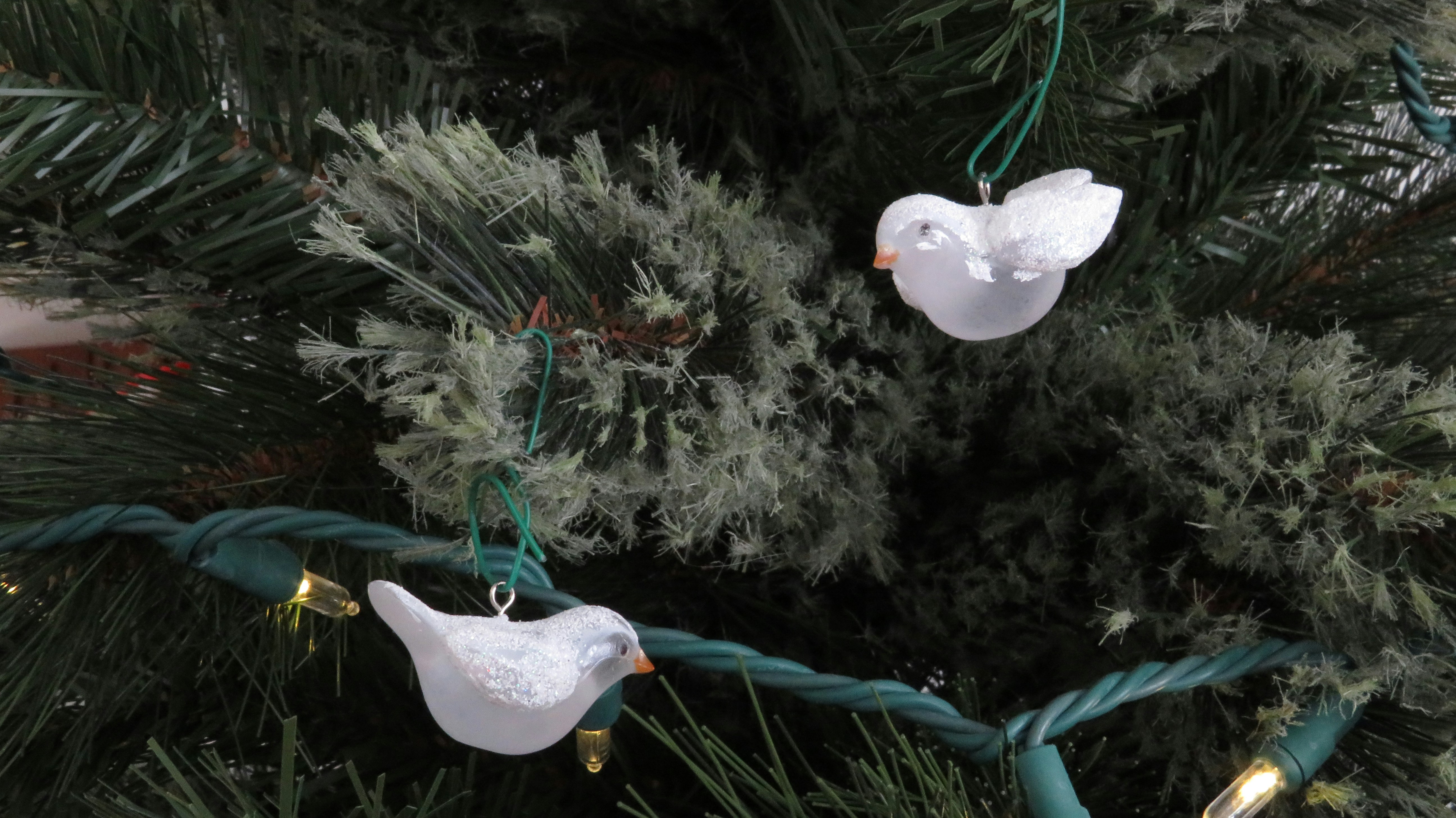 White Dove Ornaments Dotted Among Frosted Pine and Warm Lights