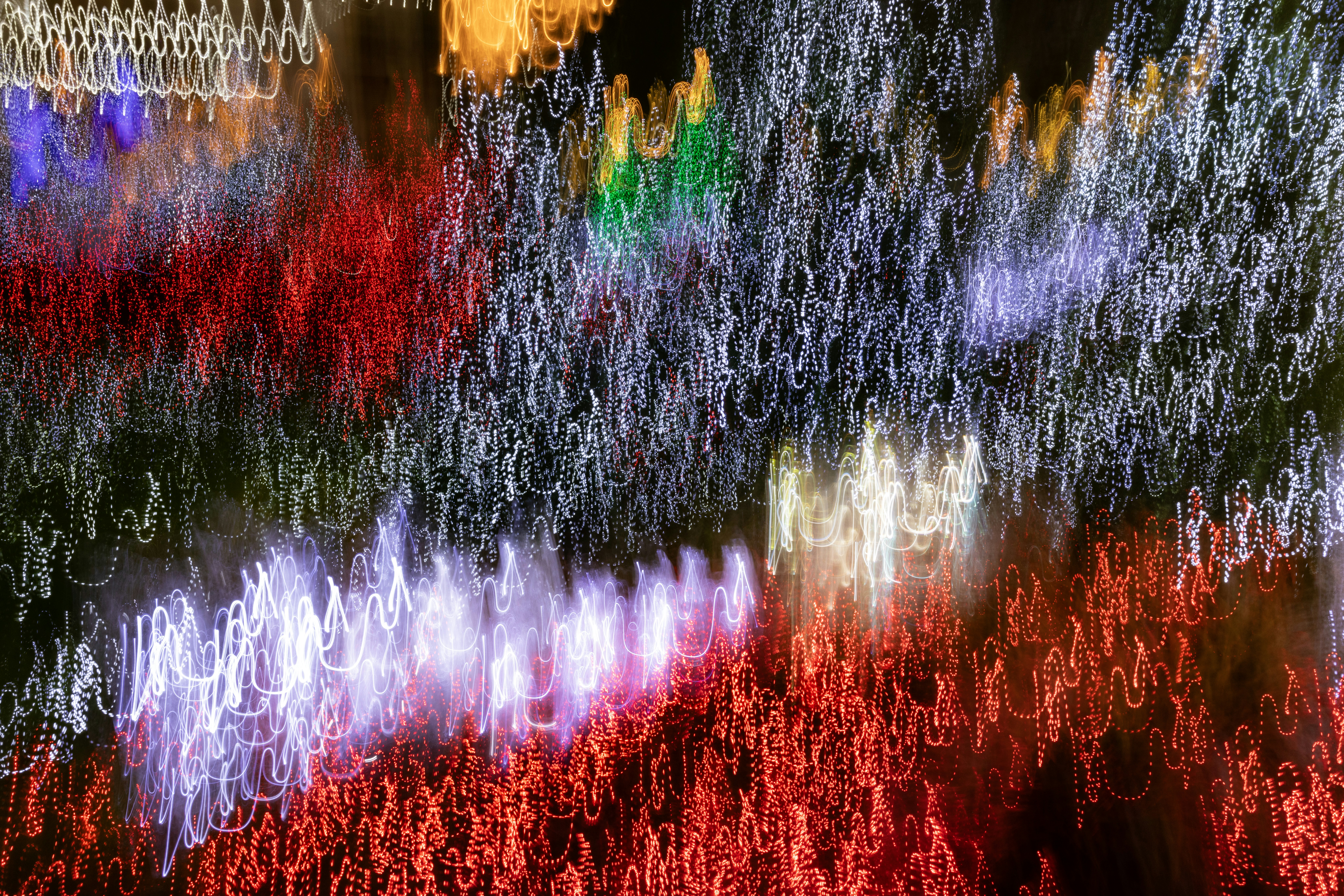 Vibrant holiday lights in abstract motion creating waves of red, white, and green hues.