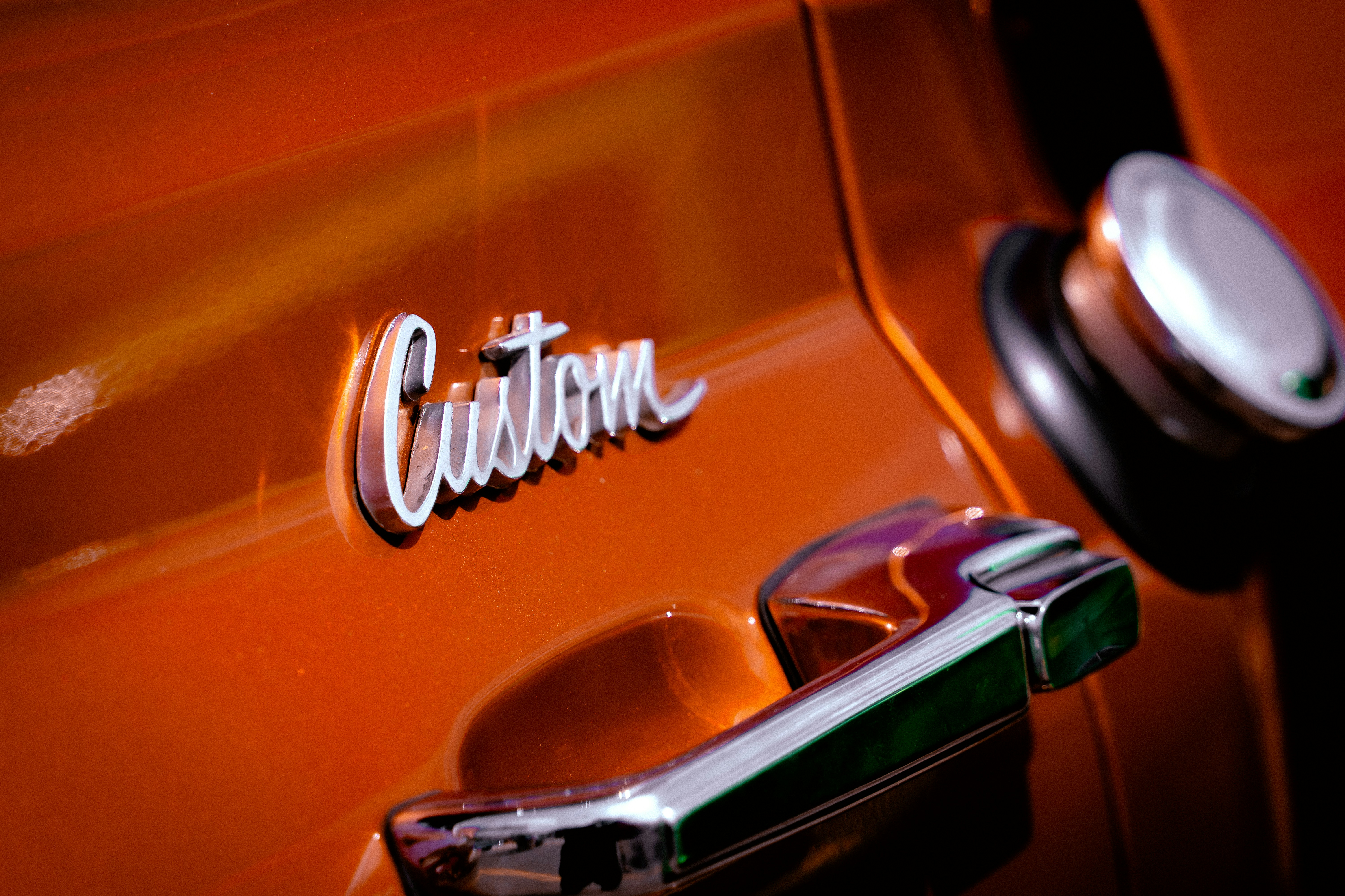 Amber Gleam on Chrome: The Custom Badge of a Vintage Orange Sedan