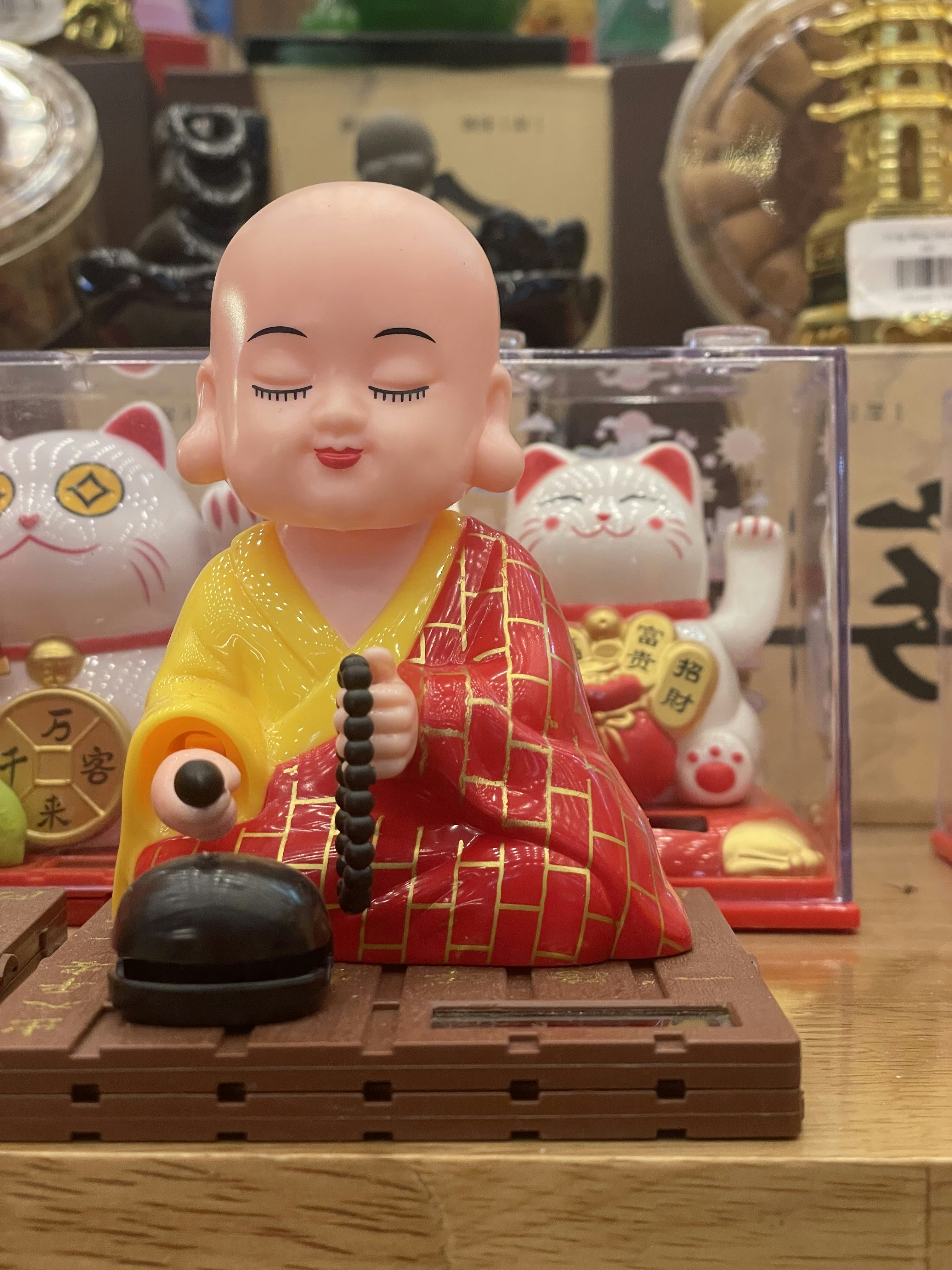 Calm Centerstage: Meditating Monk Figurine Among Lucky Cats