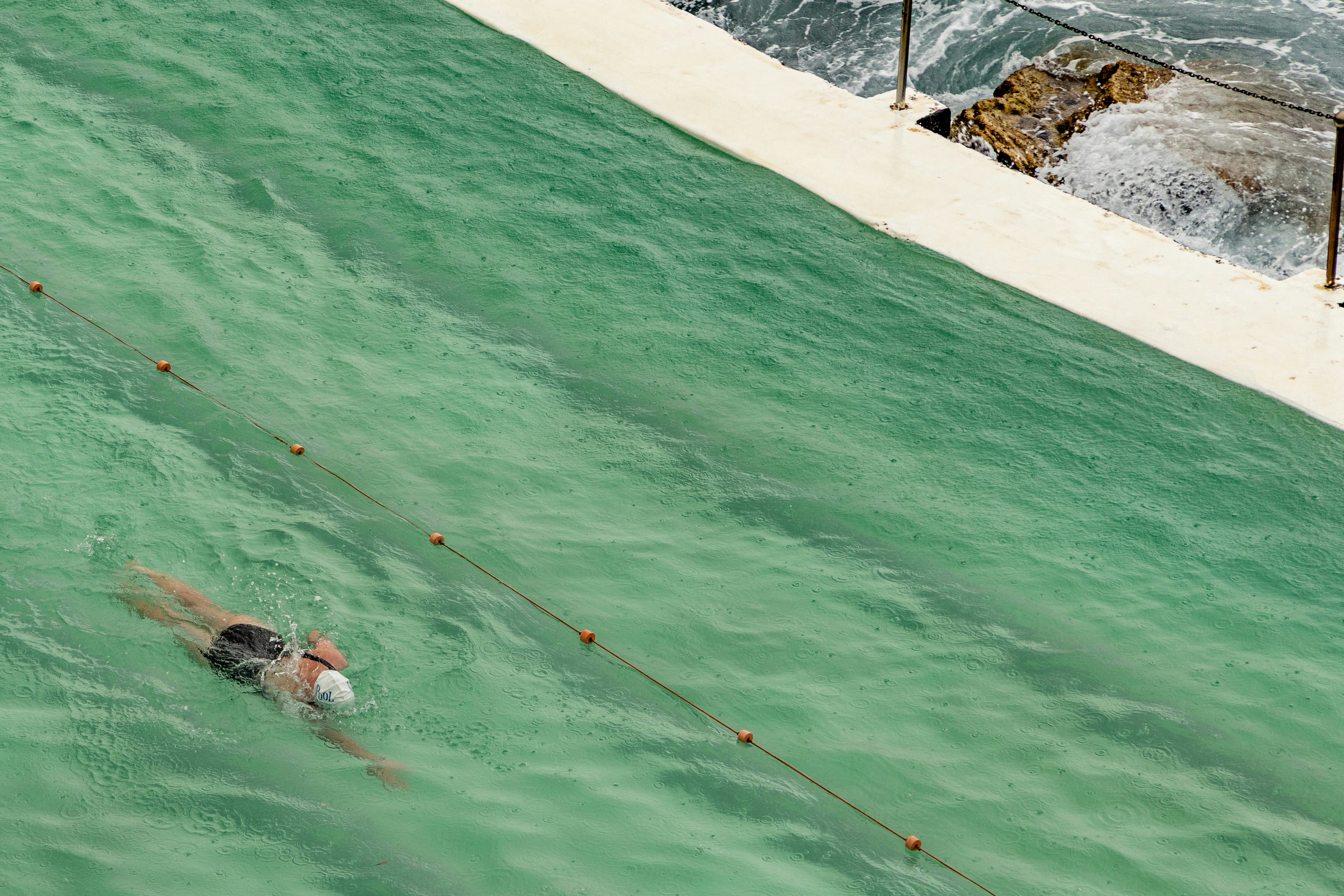 Diagonally Buoyed: A solo swimmer in jade-green water