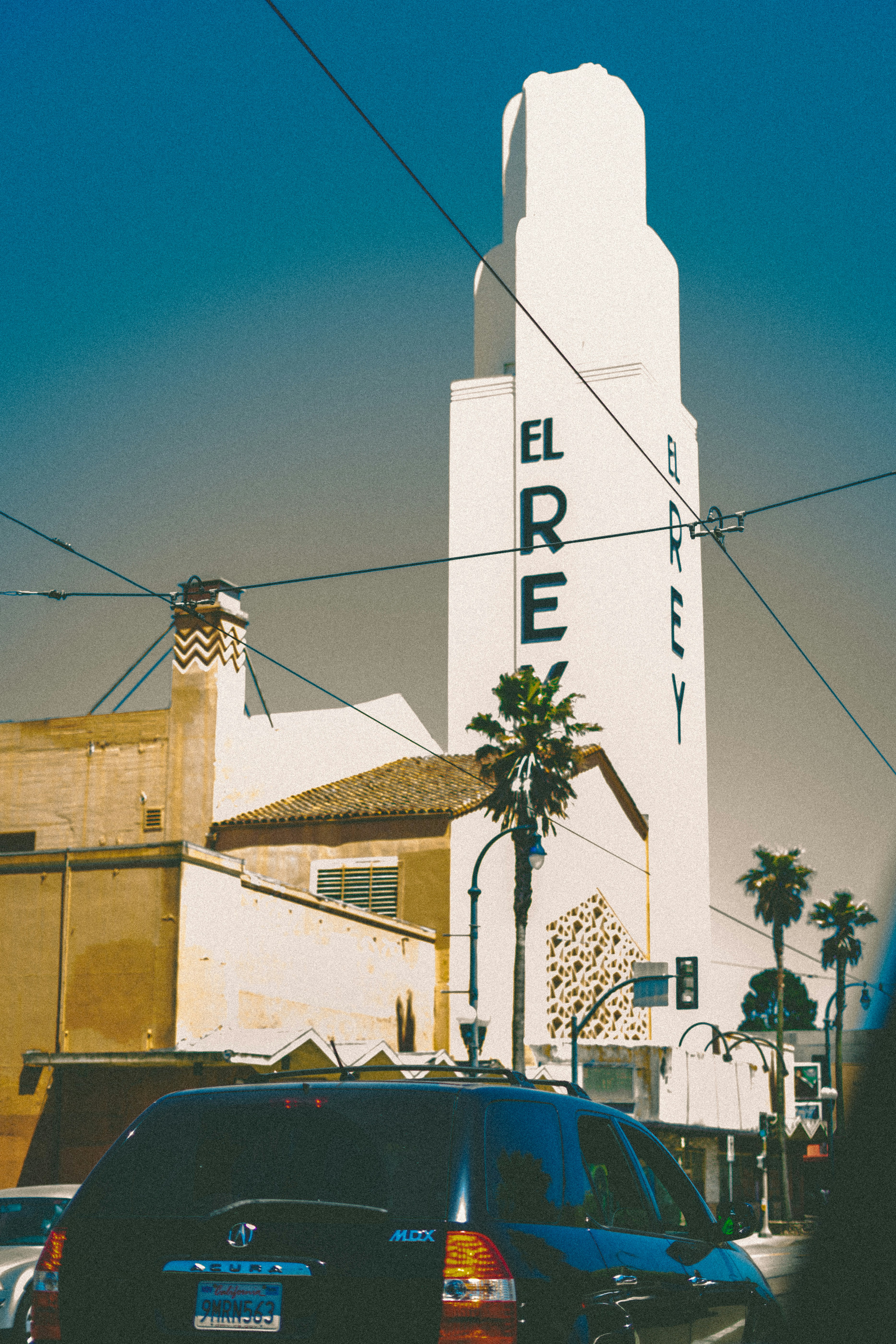El Rey Tower Rising Over a Palm-Lined Boulevard