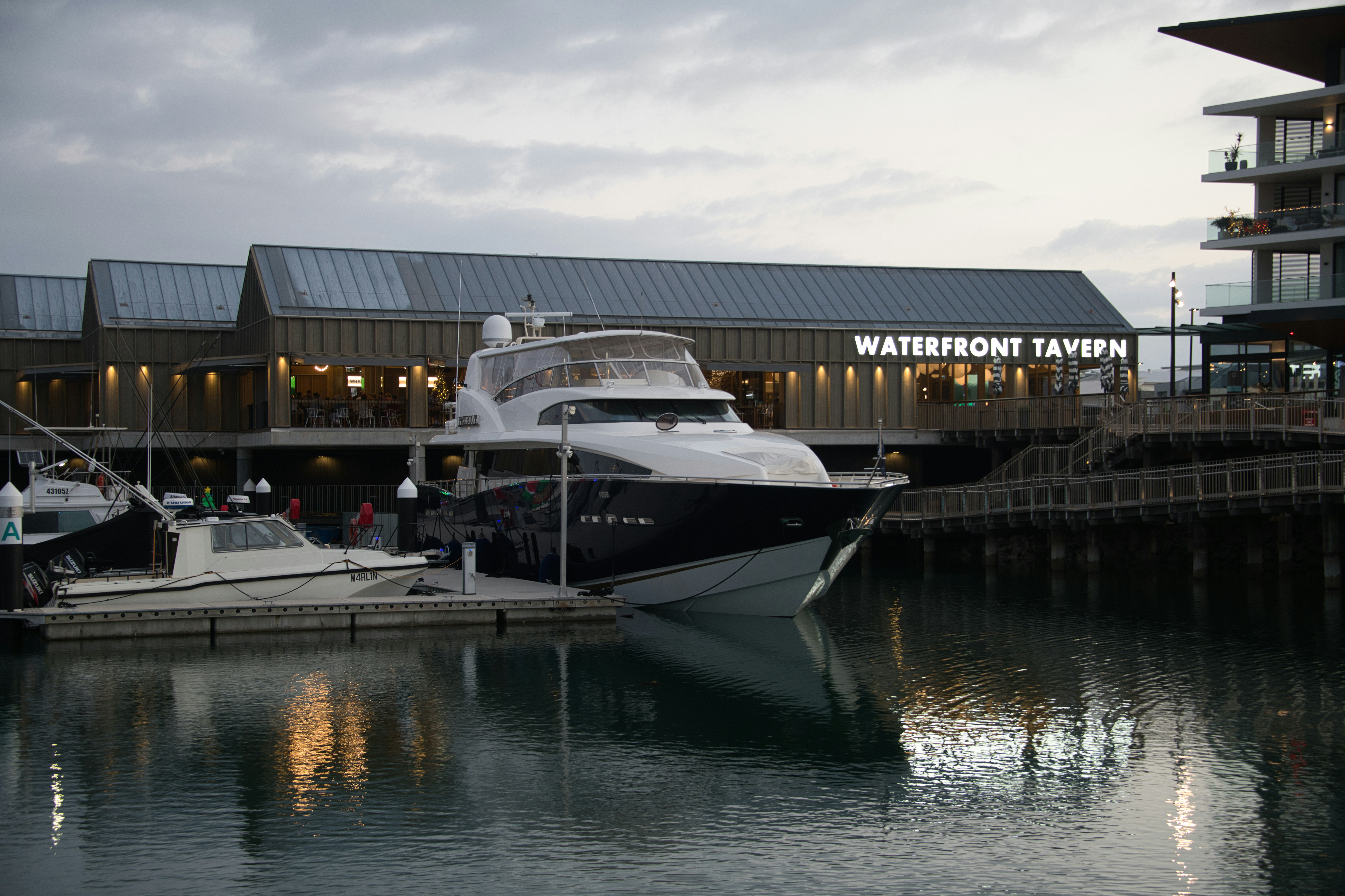A boat docked in a harbor next to a building photo – Free Shell cove ...