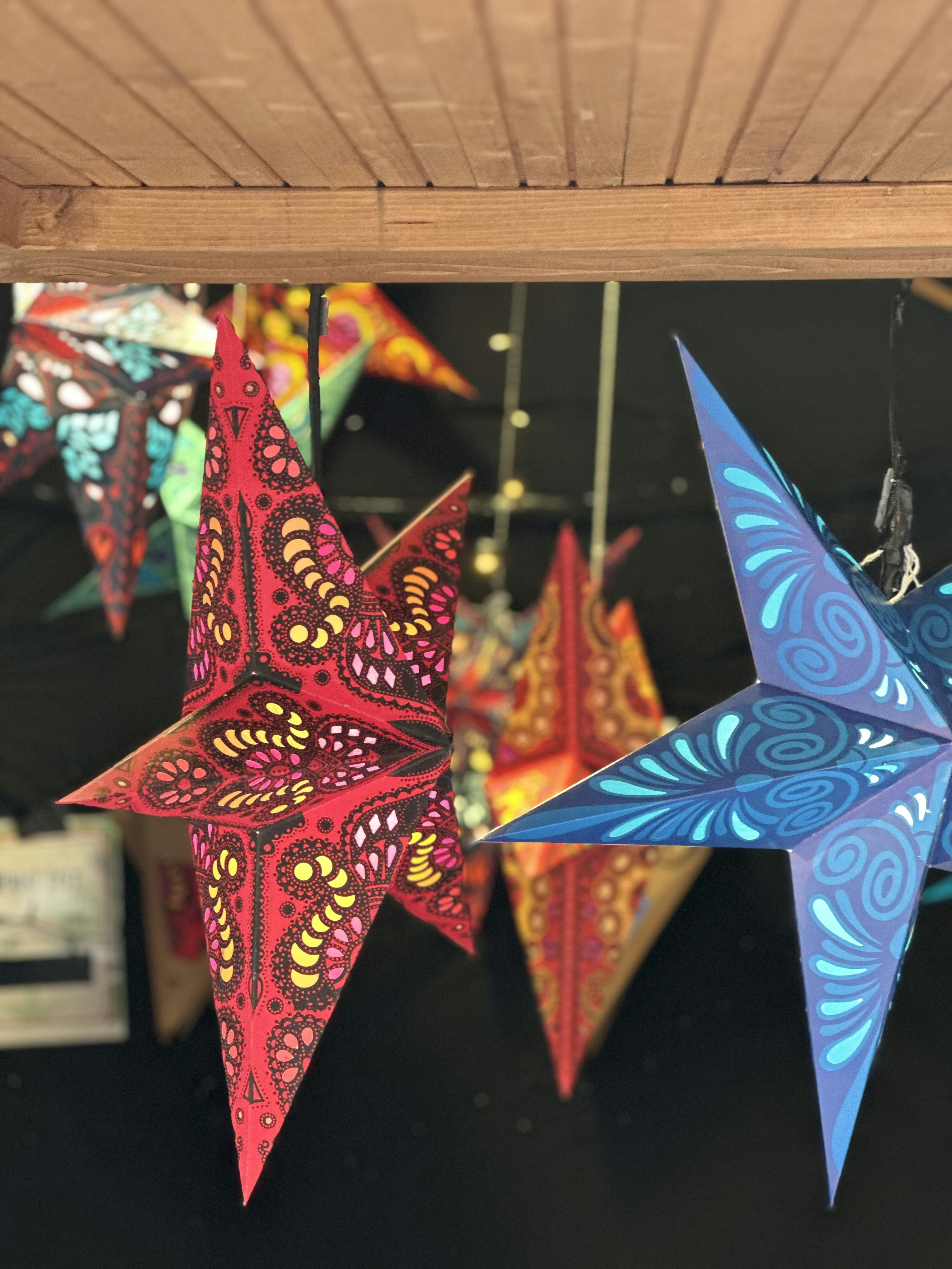 A group of colorful paper stars hanging from a ceiling photo – Free ...