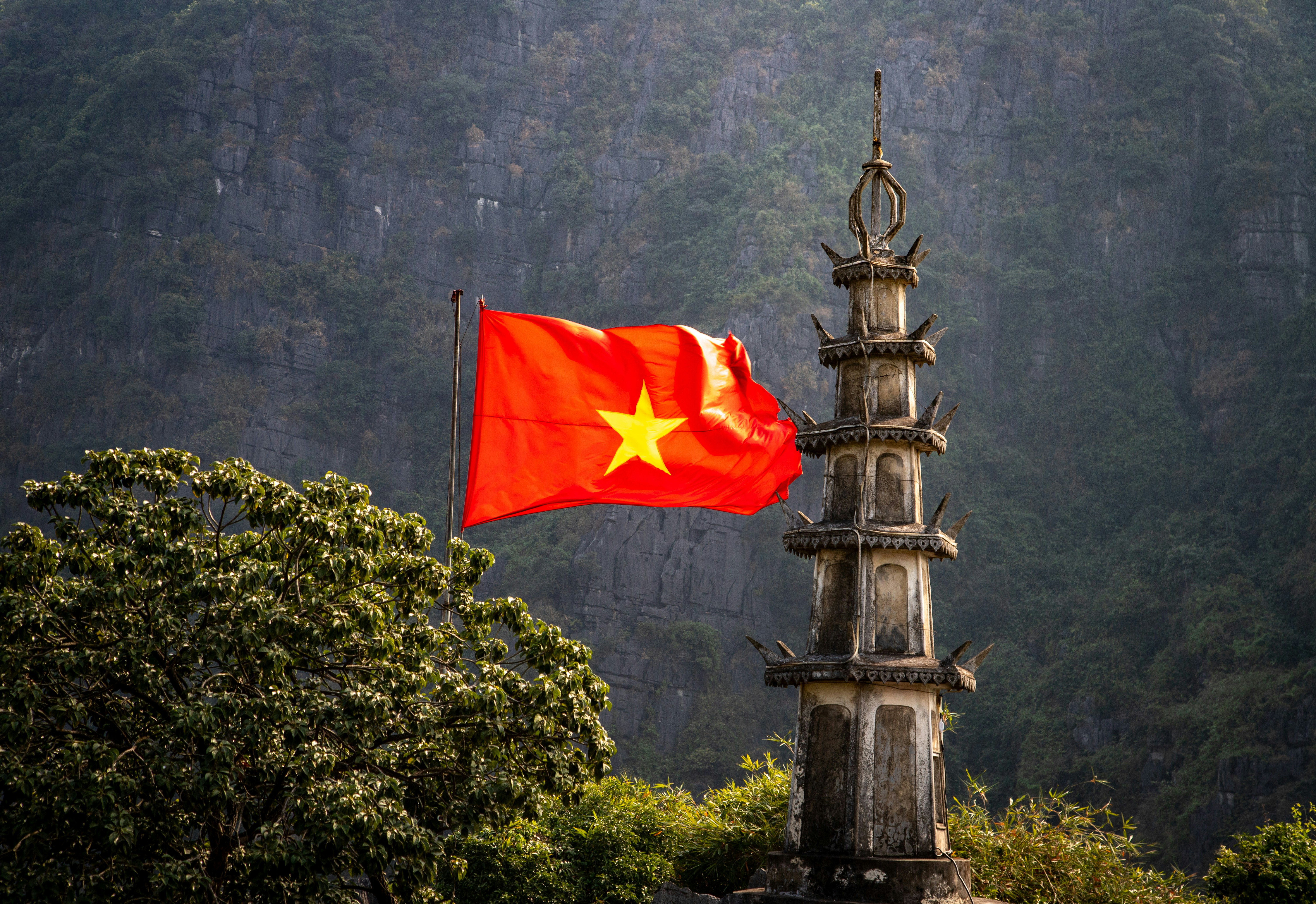 A red and yellow flag flying in front of a mountain photo – Free ...