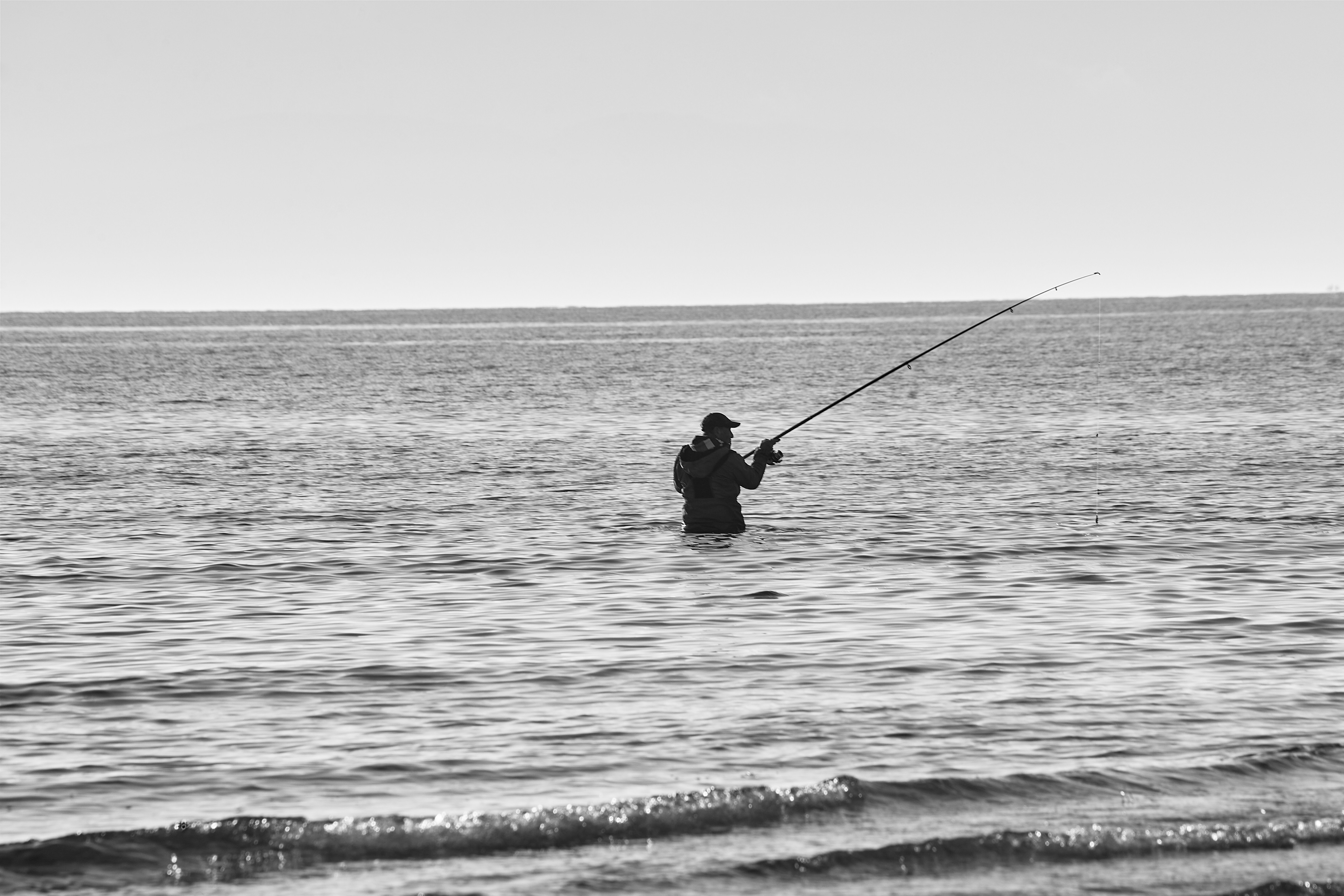 Horizon Bound: A Lone Angler Casts Silence Across Quiet Seas
