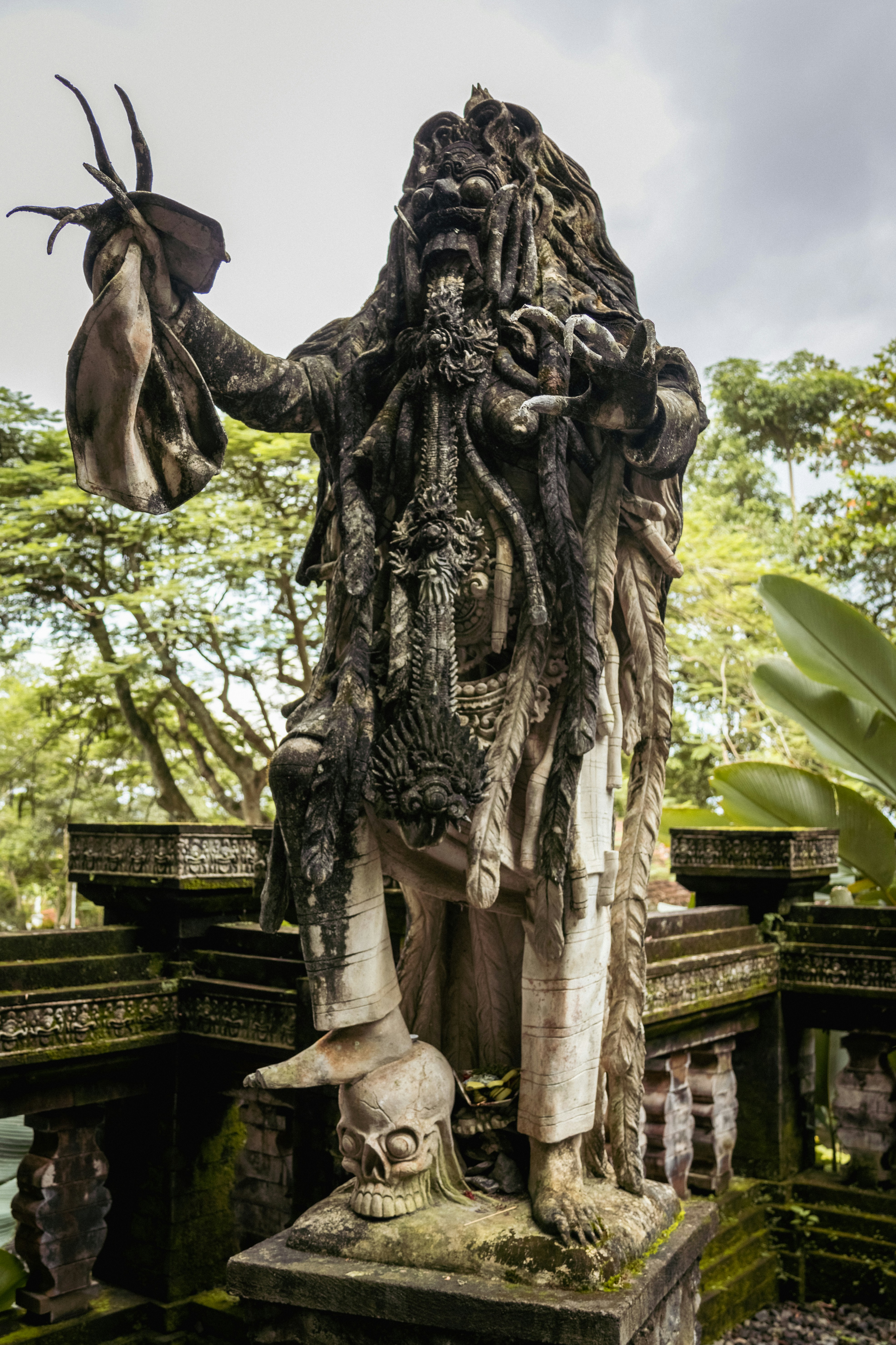 Overgrown Idol: a garland-wrapped stone guardian amid mossy temple ruins