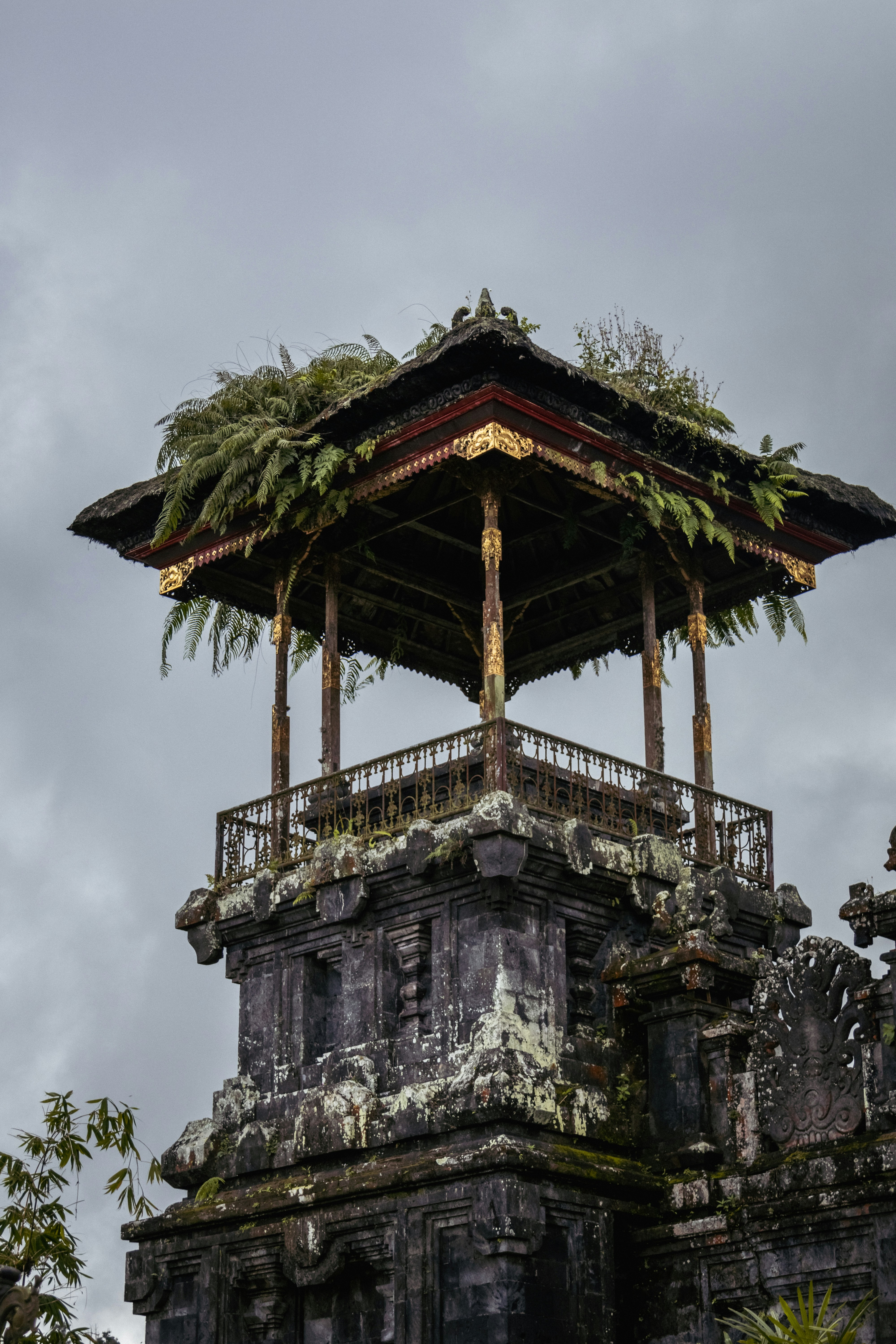 Fern-Crowned Pavilion: Time-Worn Temple Tower Beneath a Clouded Sky