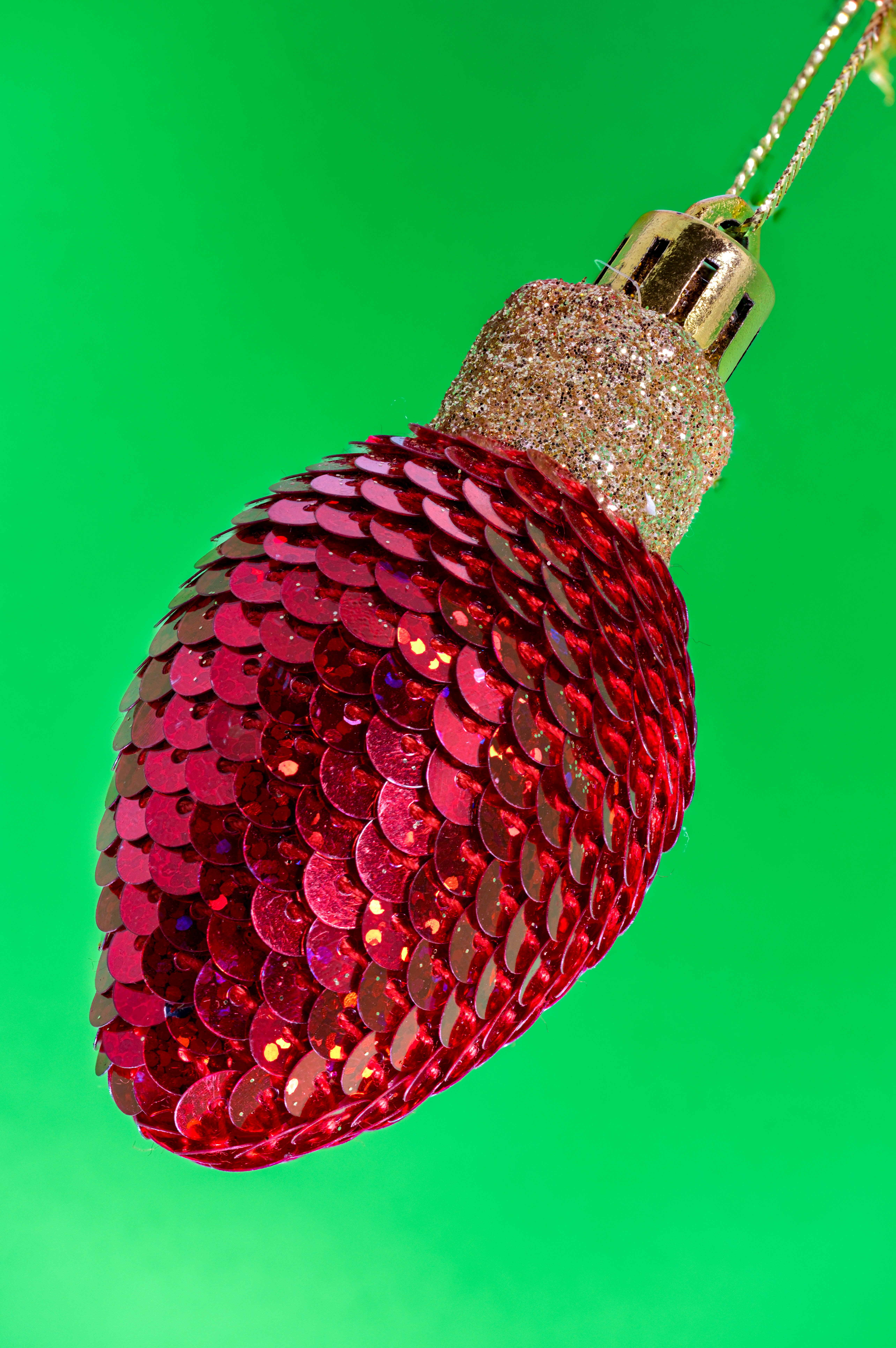Glittering Red Ornament Suspended against Neon Green Backdrop
