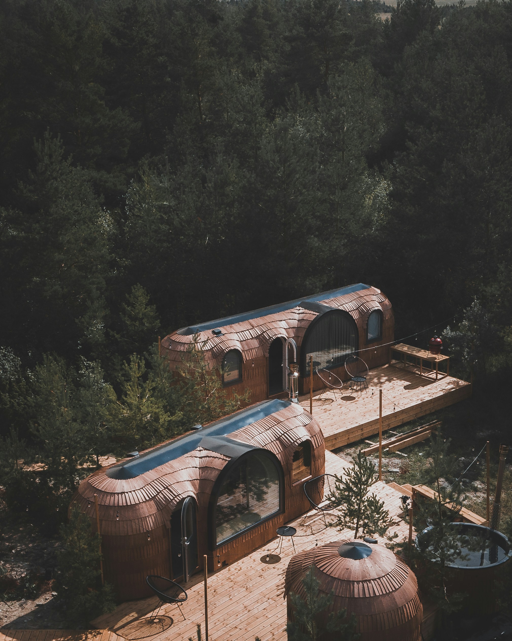 Contemporary wooden cabins and sauna surrounded by dense forest foliage.