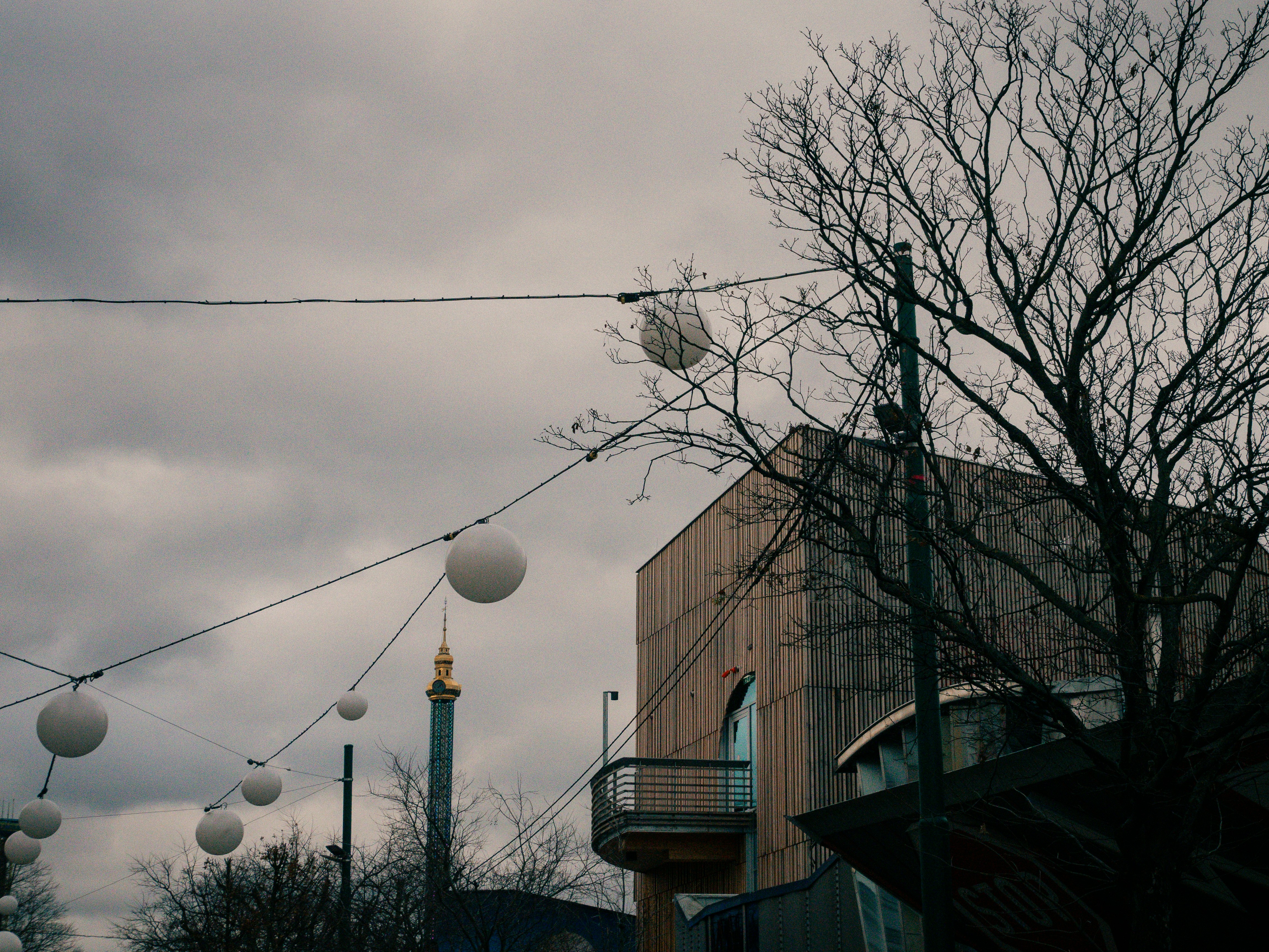 Lantern Strings Over an Overcast Boulevard: The Distant Golden Spire