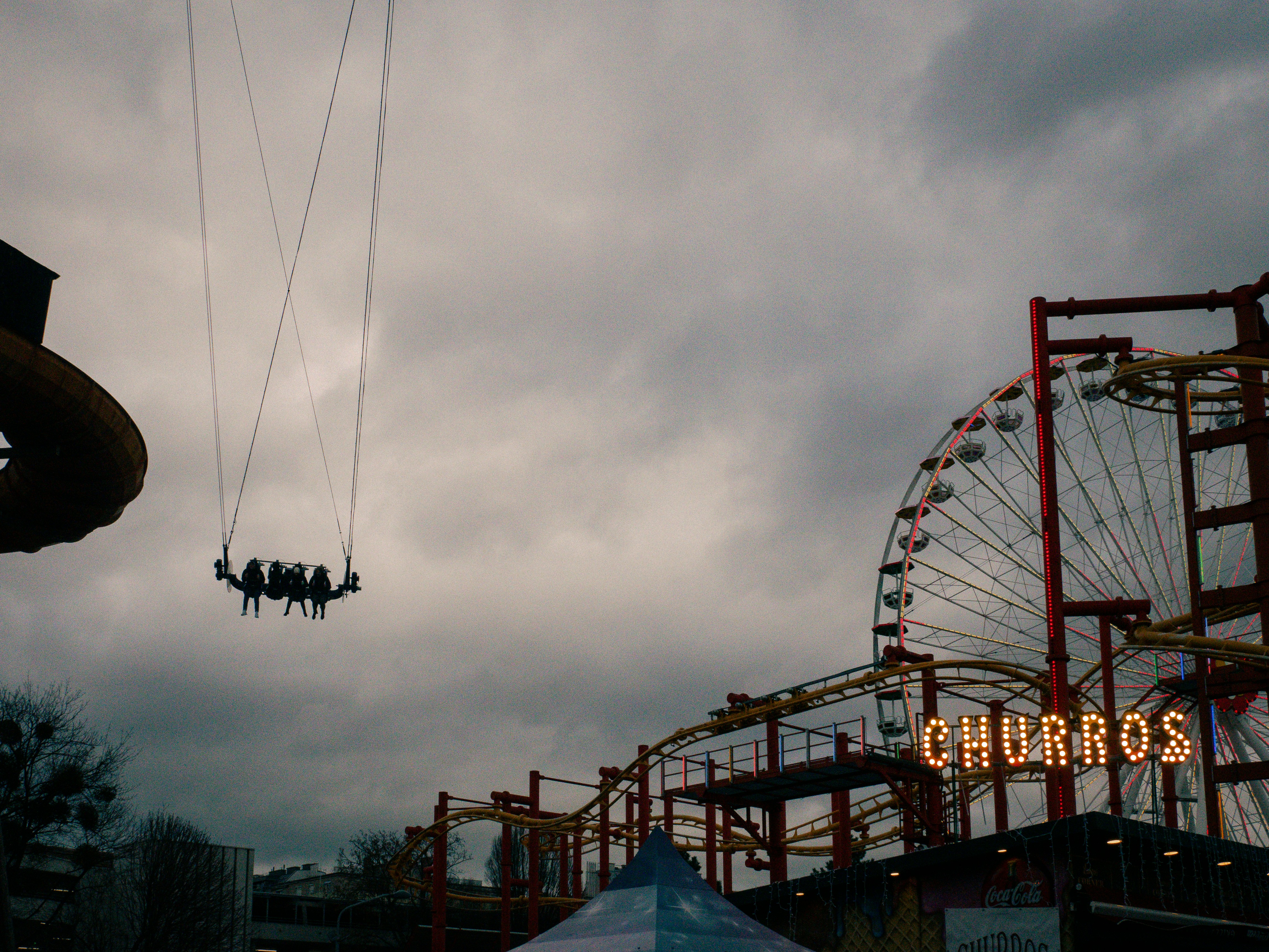 Swing-ride silhouettes under a clouded carnival sky
