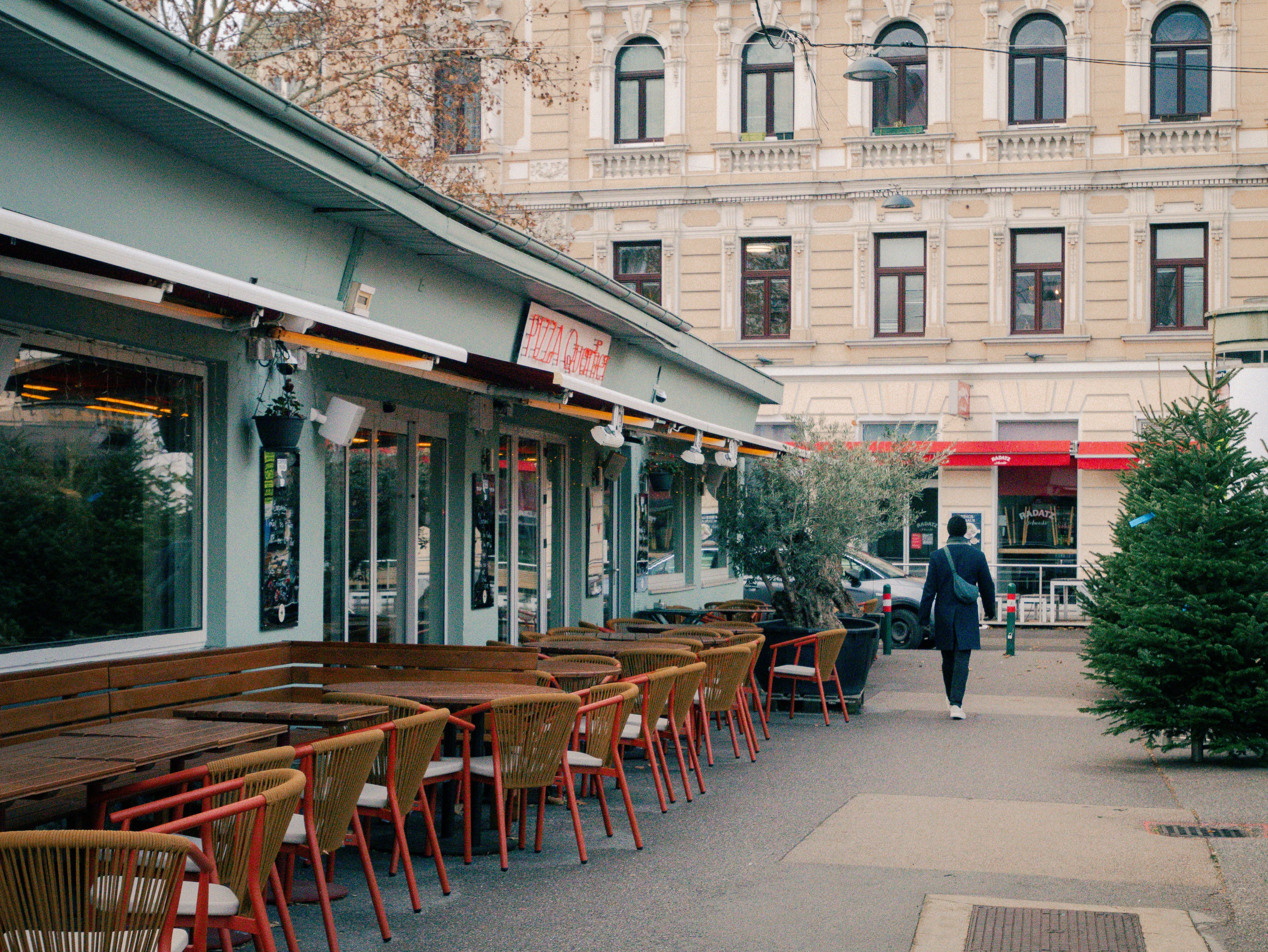 Cafe Row in Soft Daylight: Chairs, Glass, and a Distant Pedestrian