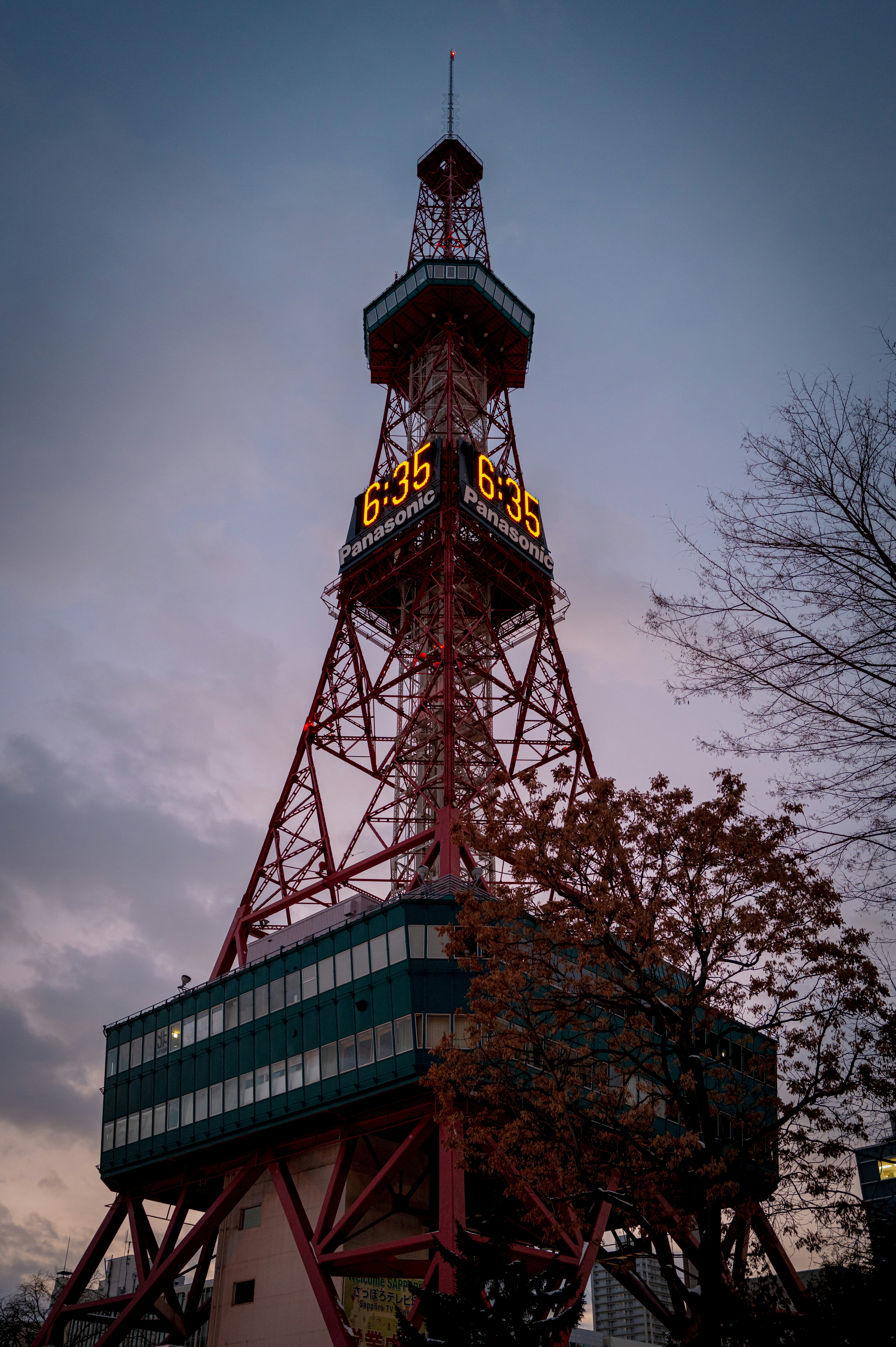 Dusk Over a Red Lattice Clock Tower with Neon Timeboards