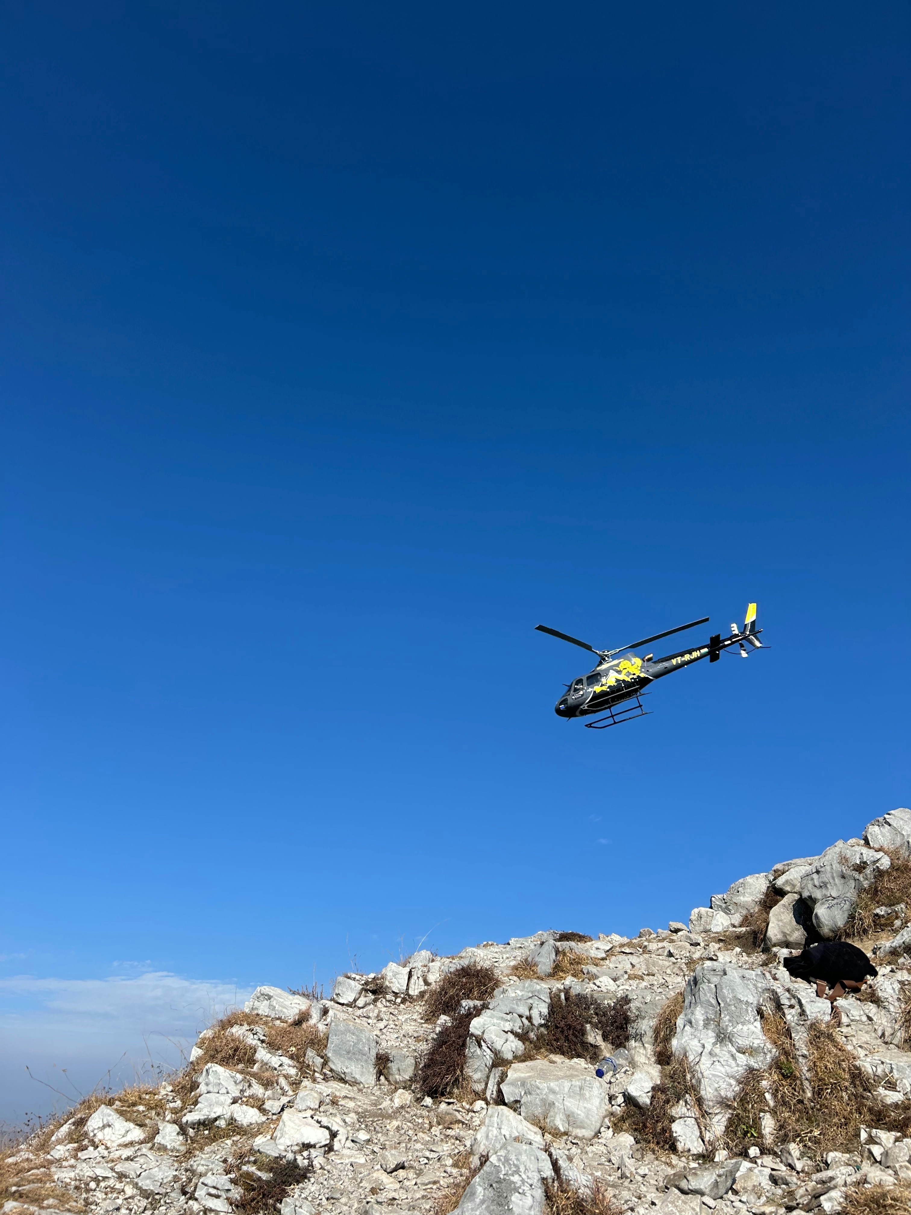 Yellow rescue chopper skims the alpine ridge under a cobalt sky