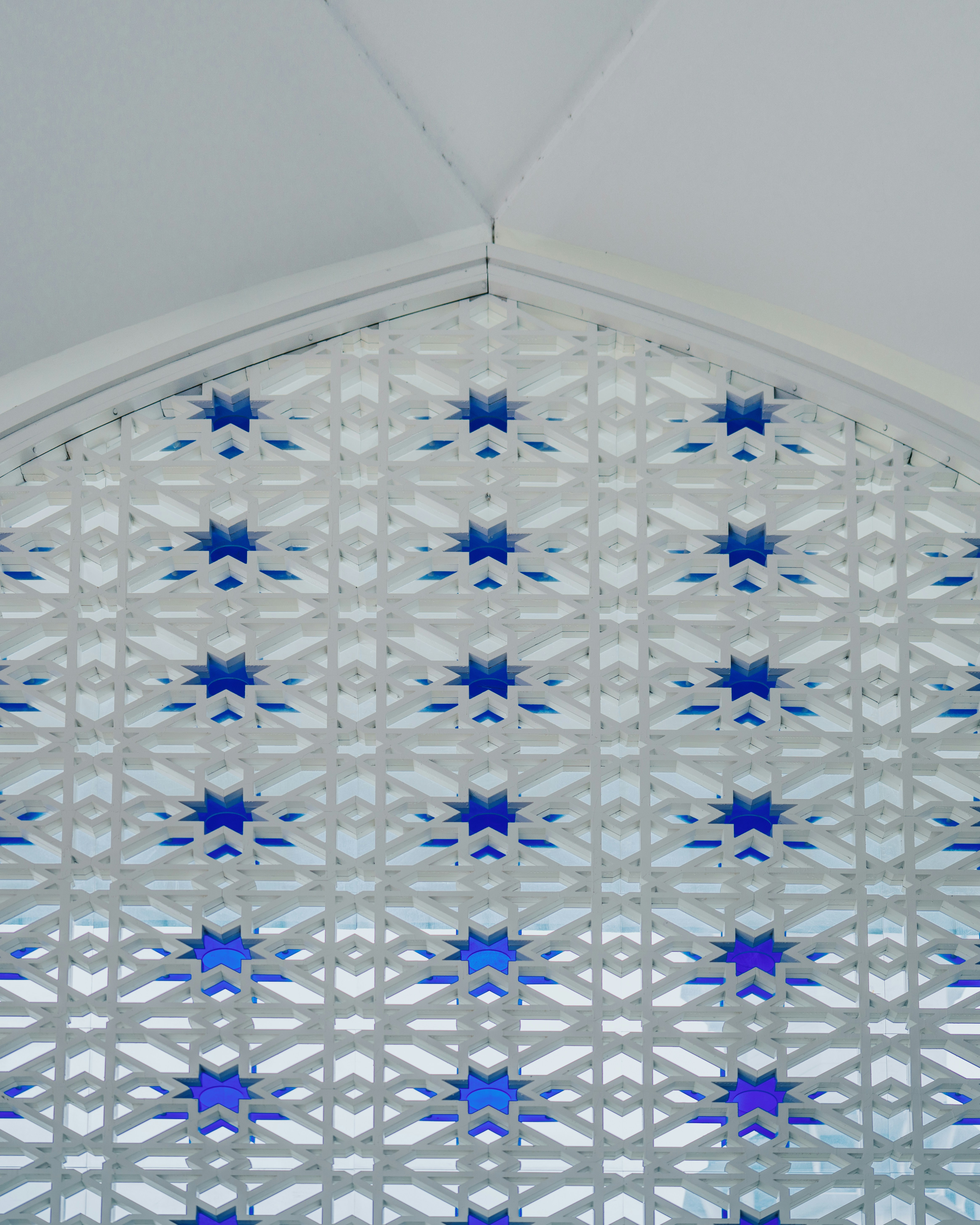 Photograph of a white lattice wall adorned with blue star motifs in a repeating geometric pattern.