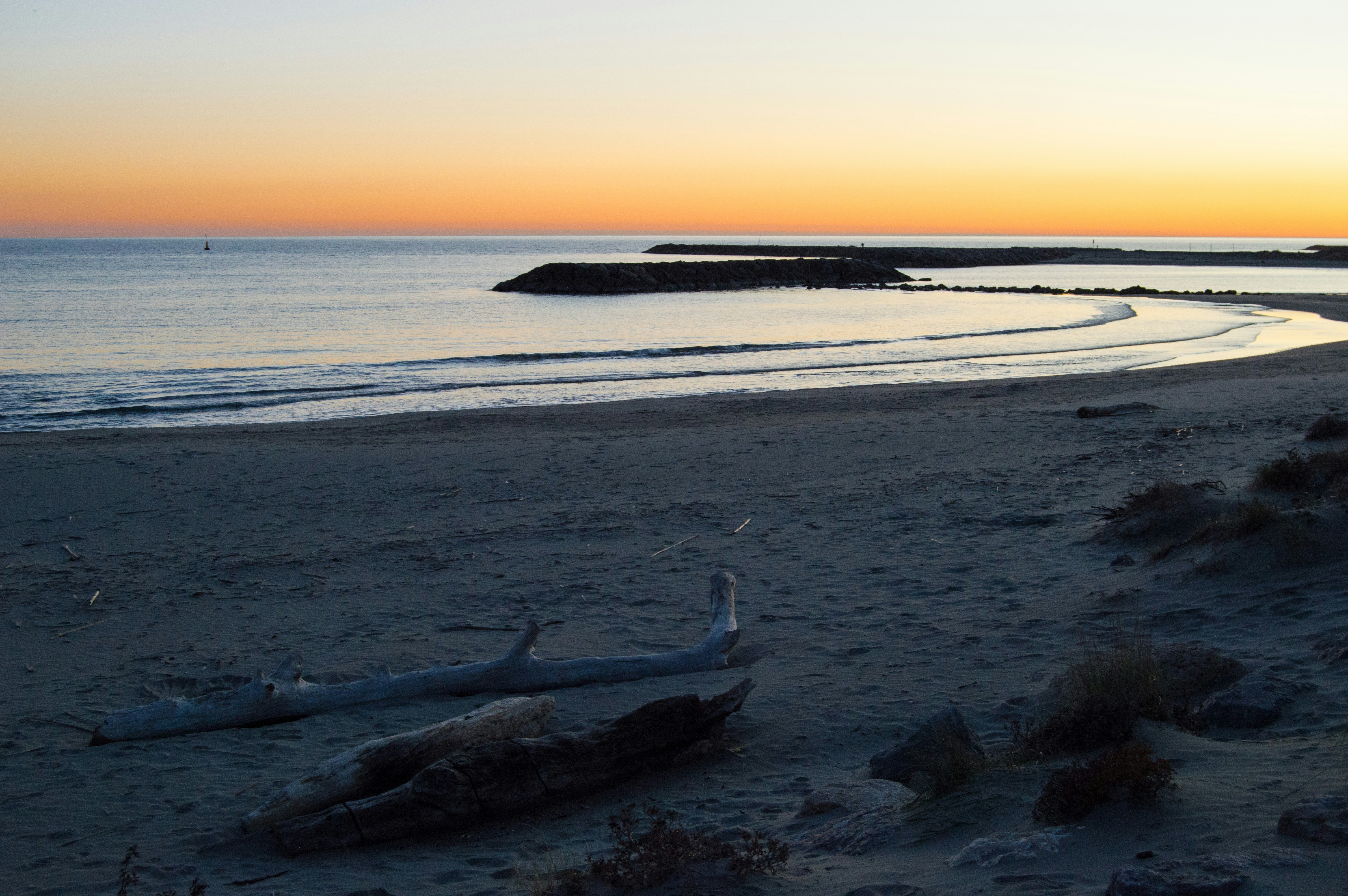 A beach at sunset with a log laying on the sand photo – Free France ...