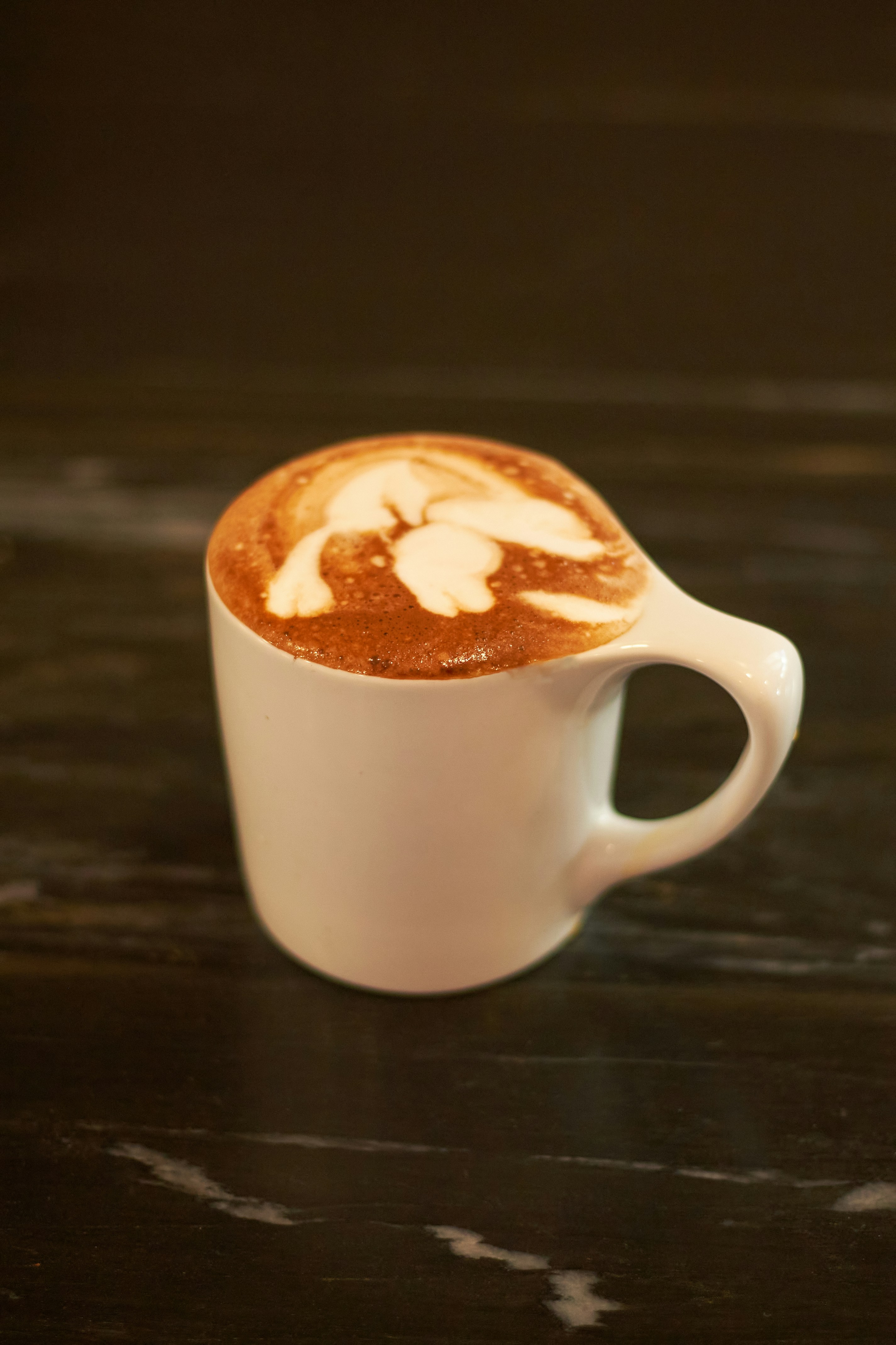 Latte Art on a White Ceramic Cup Bathed in Warm Wood Tones