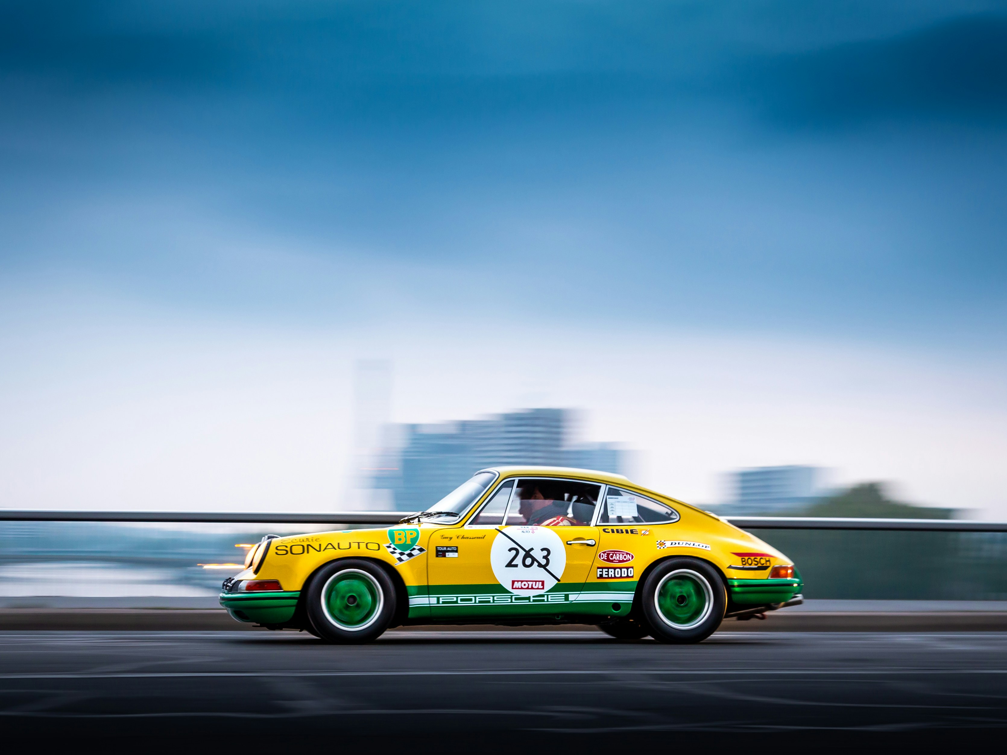 A yellow and green car driving down a street photo – Free Car Image on ...