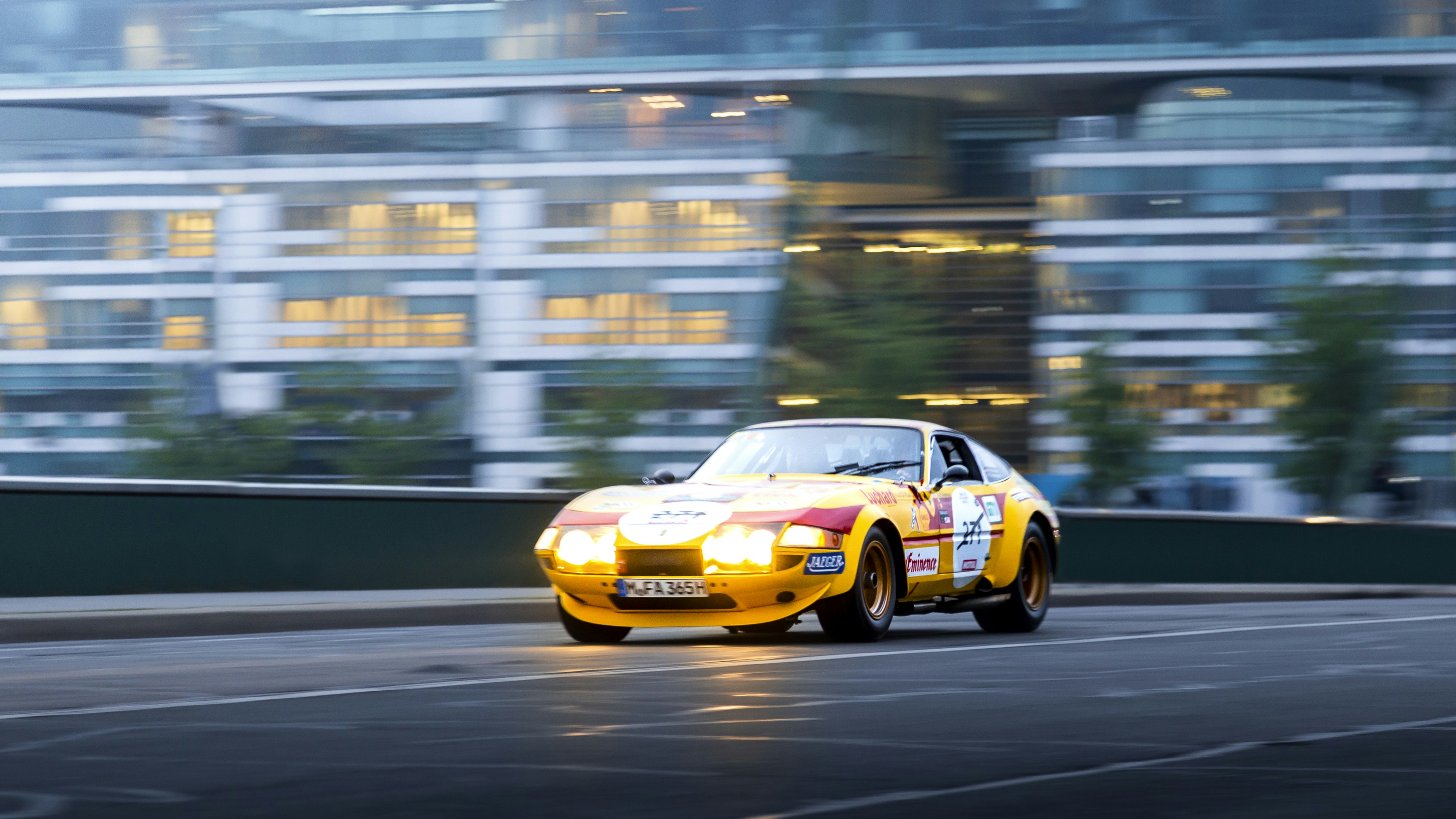 A yellow sports car driving down a city street photo – Free Car Image ...