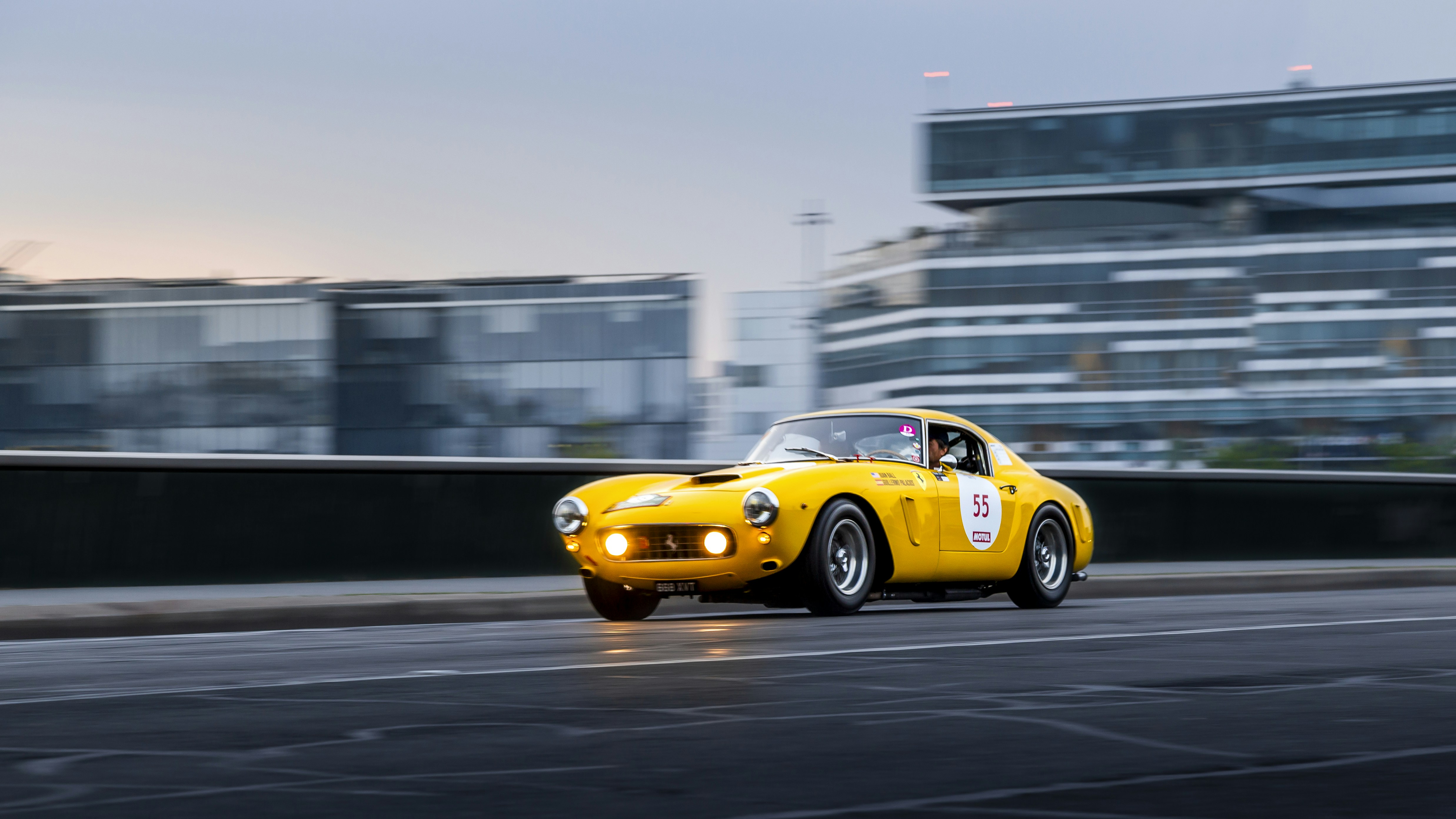 A yellow sports car driving down a city street photo – Free Car Image ...