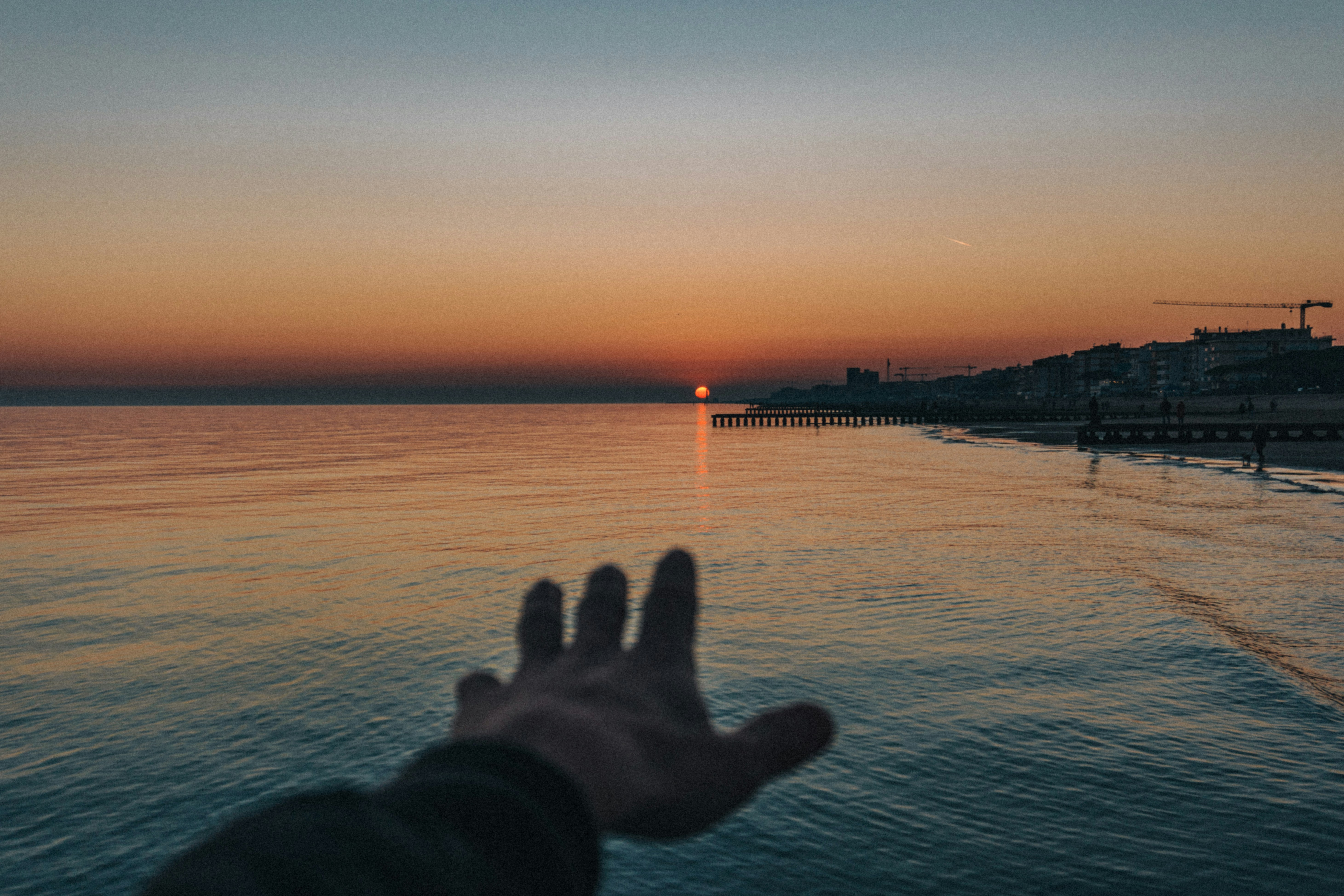 A hand reaching out towards the ocean at sunset photo – Free Beach ...