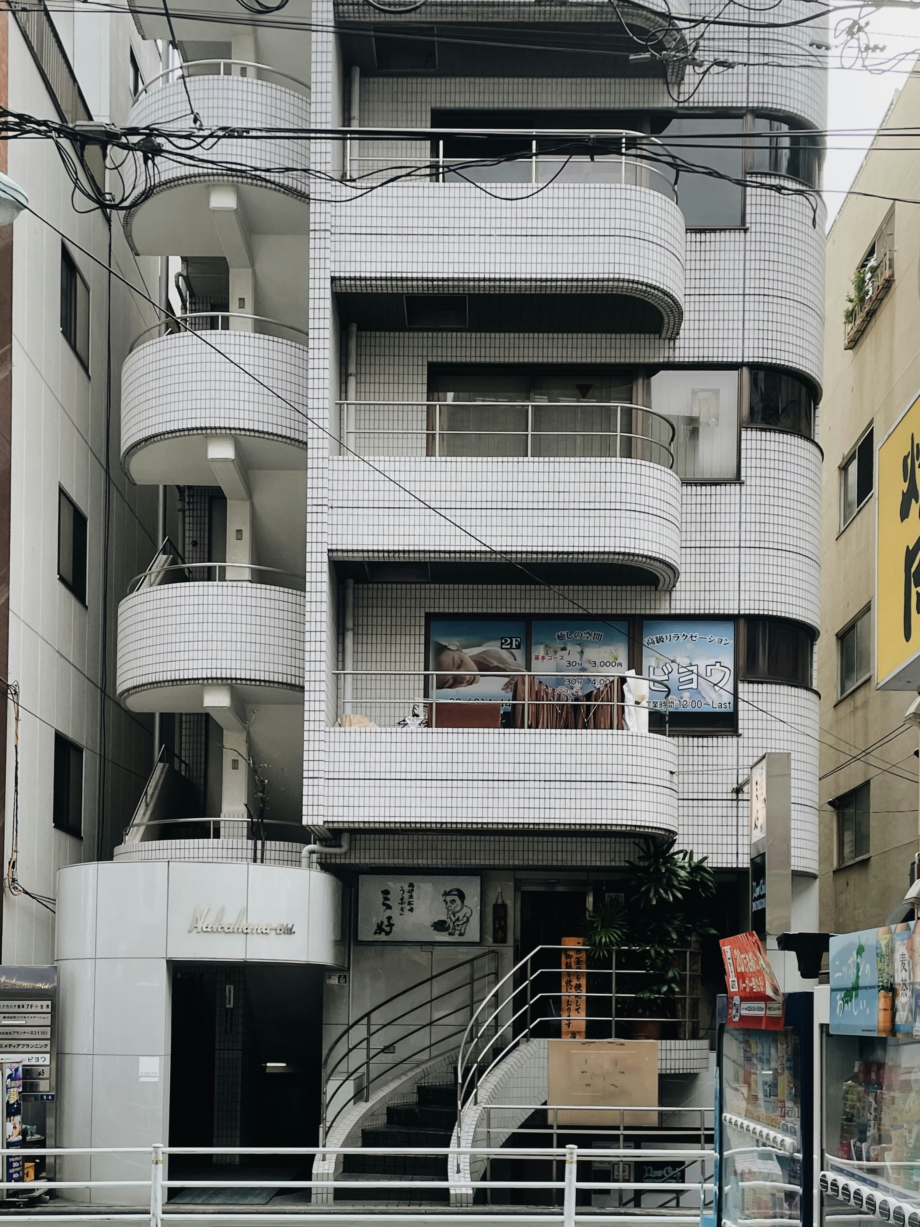 Cascading Curves: A White-Tiled Urban Facade's Spiral Staircase