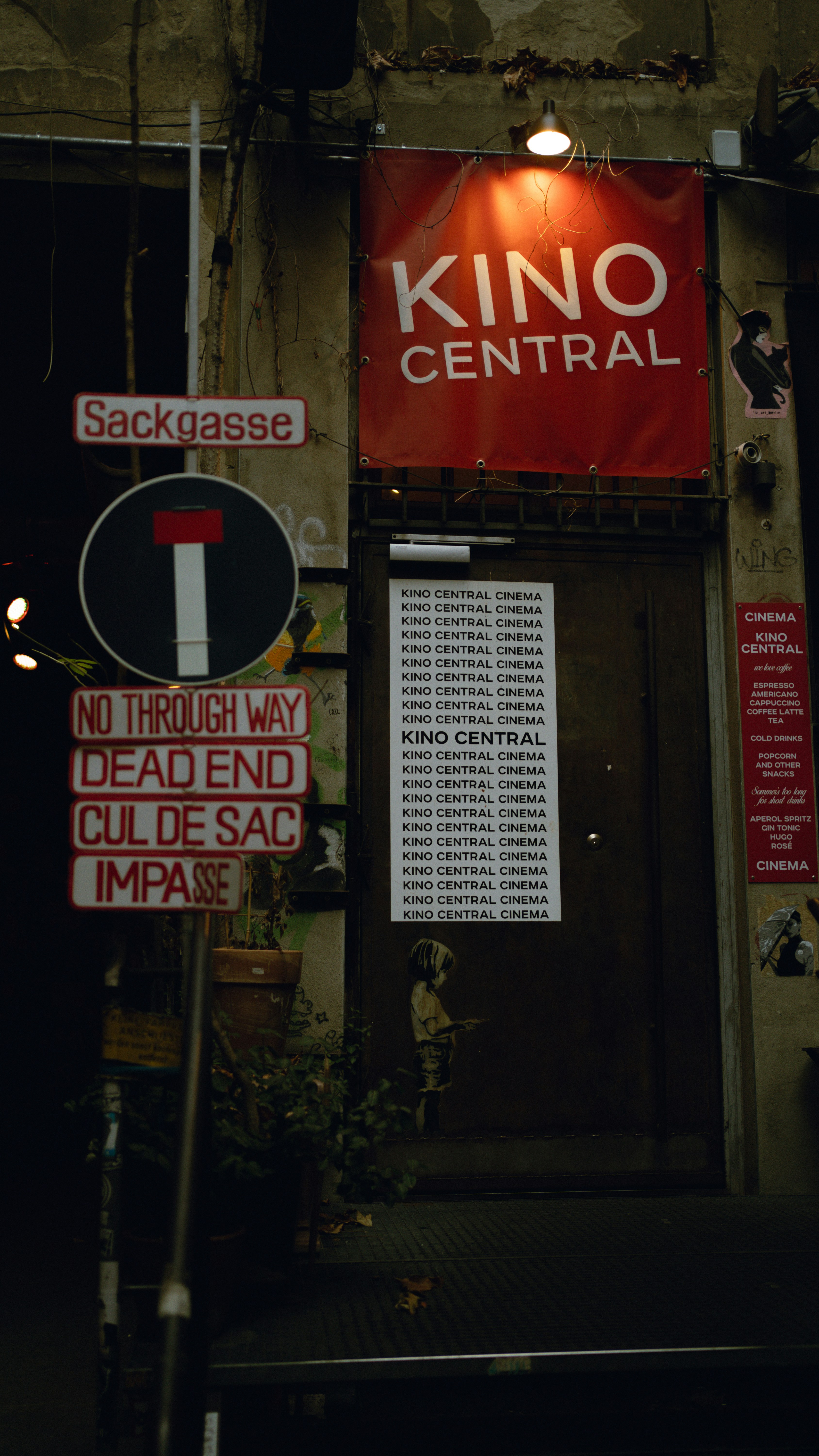 Kino Central: Red Cinema Banner Over a Narrow Urban Corridor