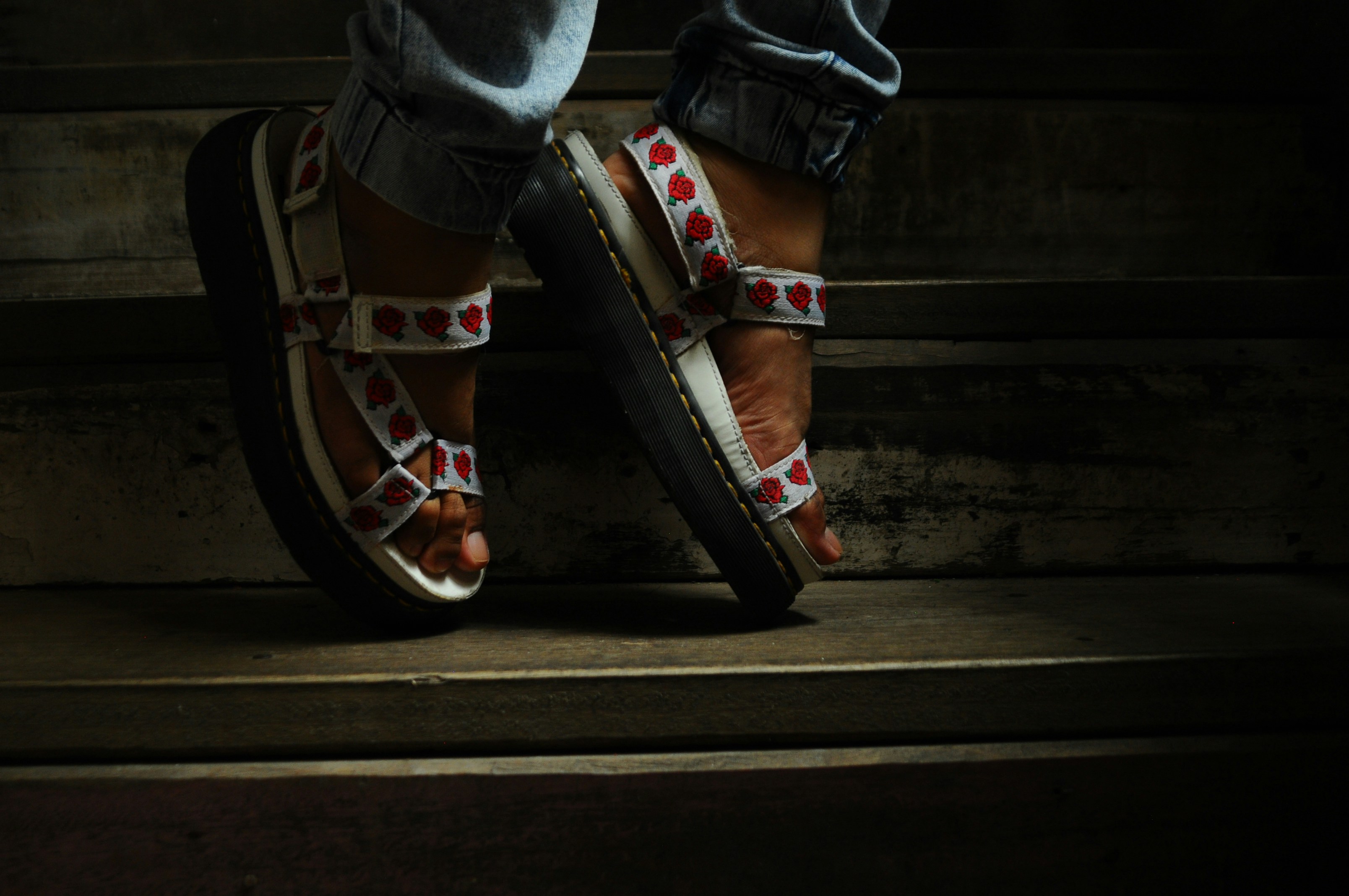 Feet in heart-patterned sandals stepping down dimly lit stairs.