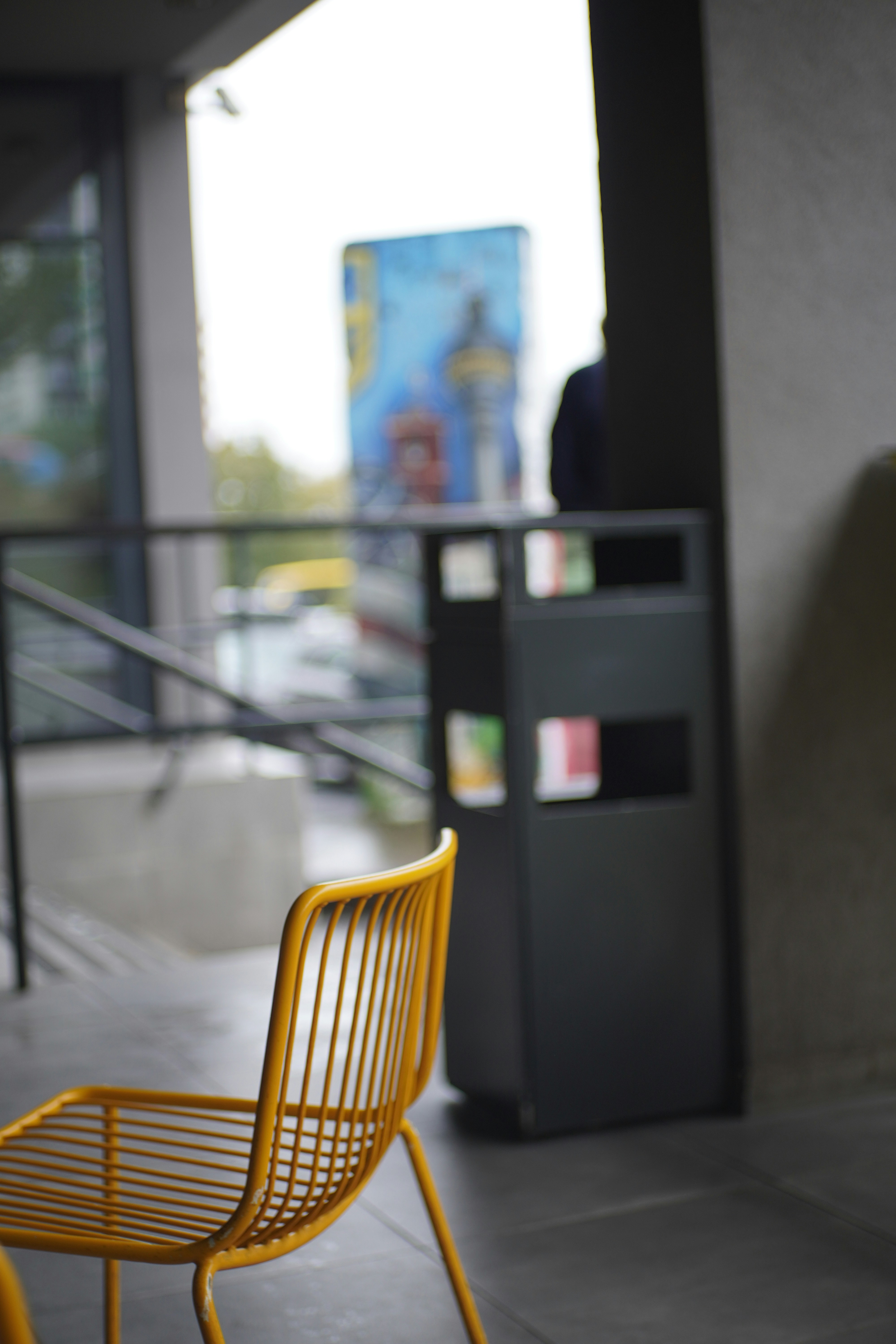 Solitary Yellow Wire Chair Against a Blur of Urban Architecture