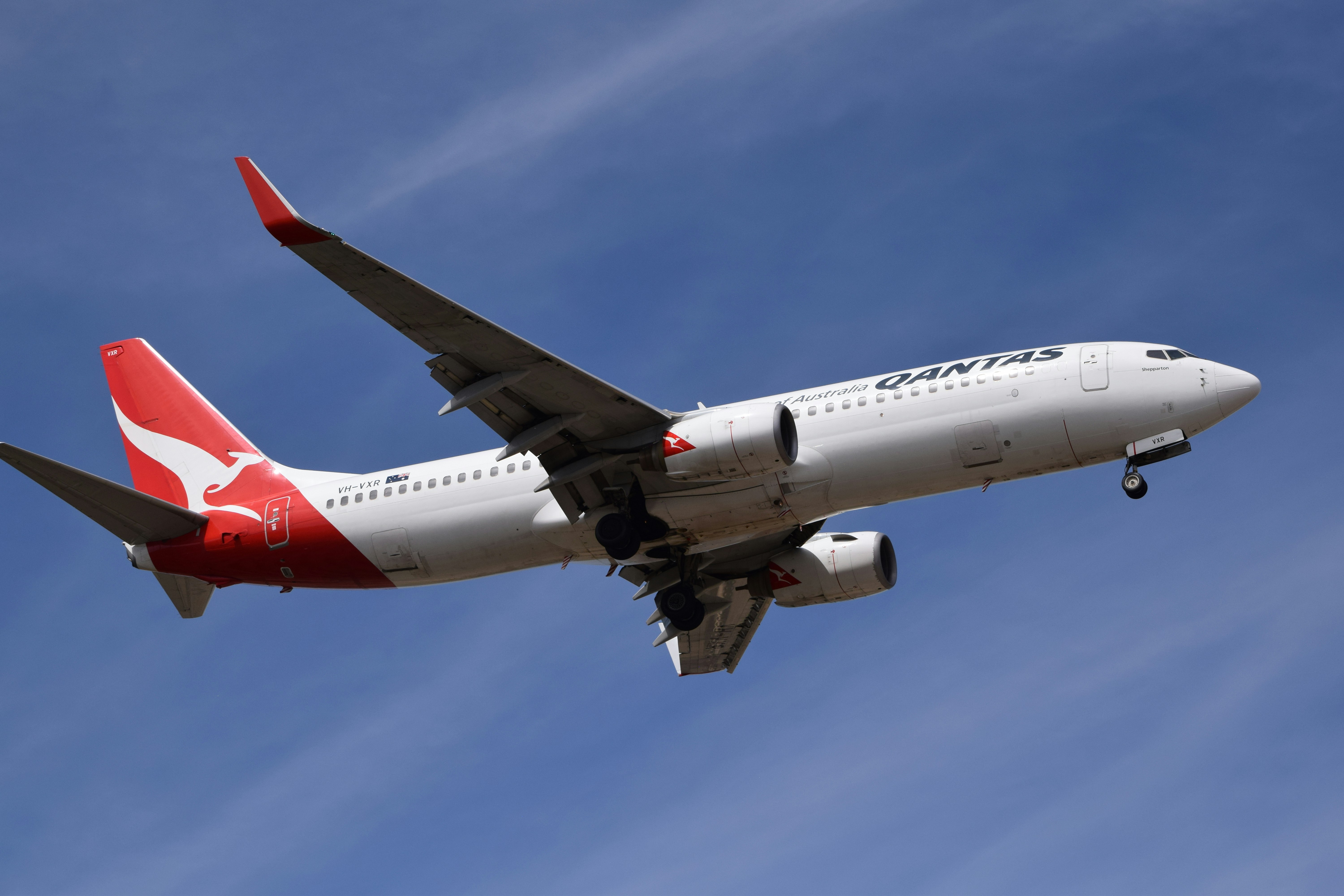 A large passenger jet flying through a blue sky photo – Free Melbourne ...