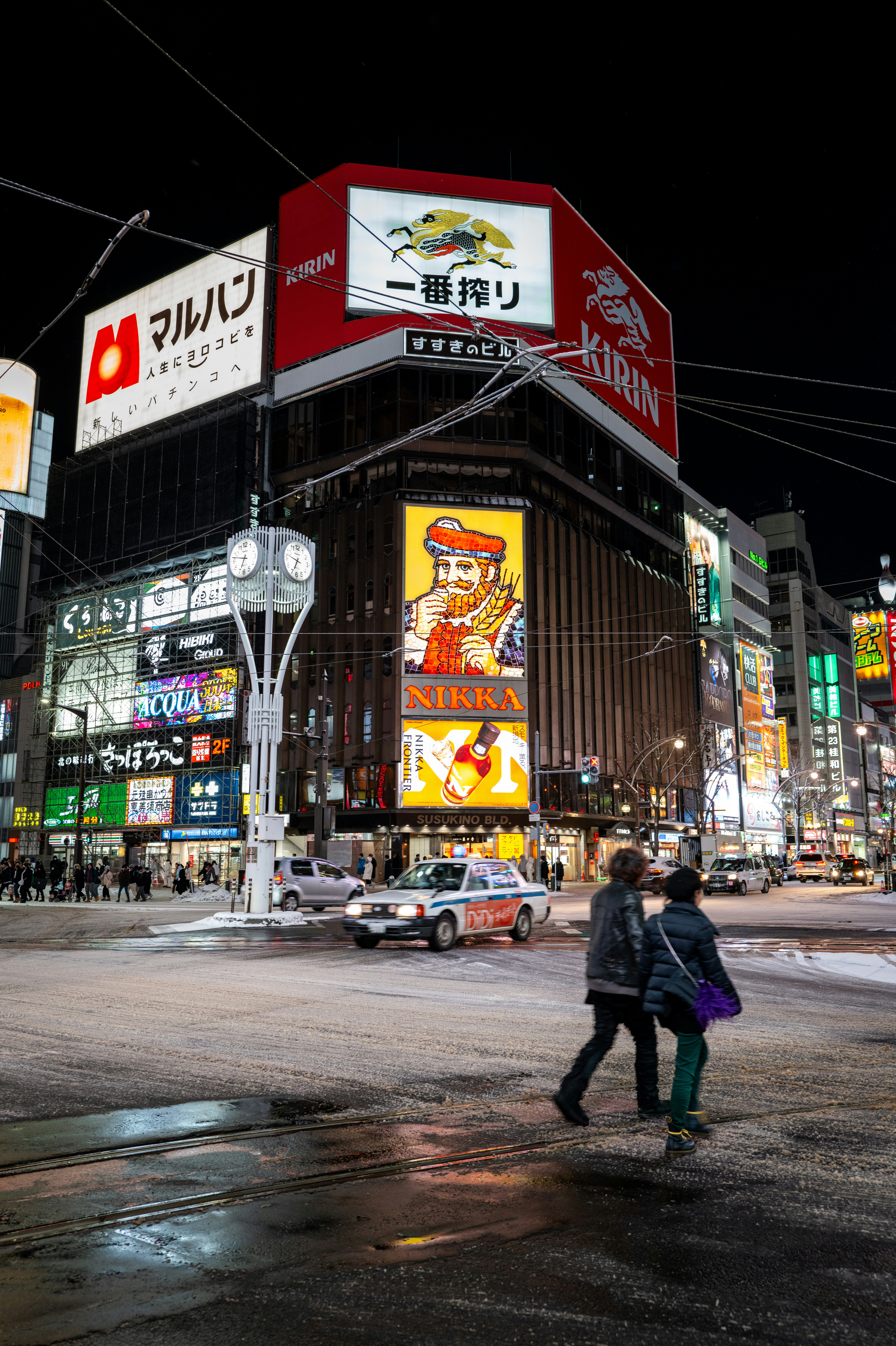 Un couple de personnes traversant une rue la nuit photo – Image ...