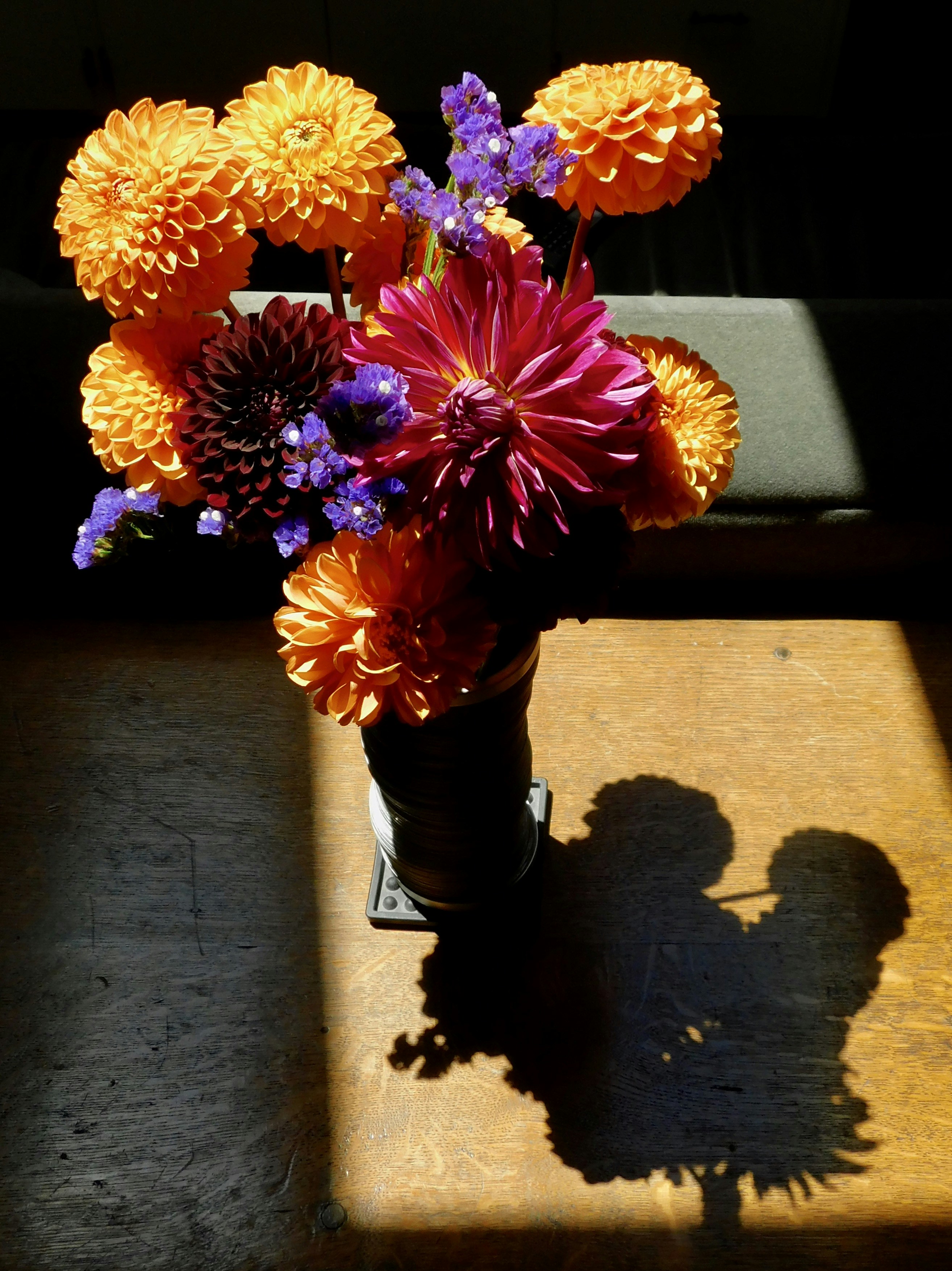 Sunlit Bouquet: Orange Dahlias and Purple Sprigs in a Quiet Window Still Life