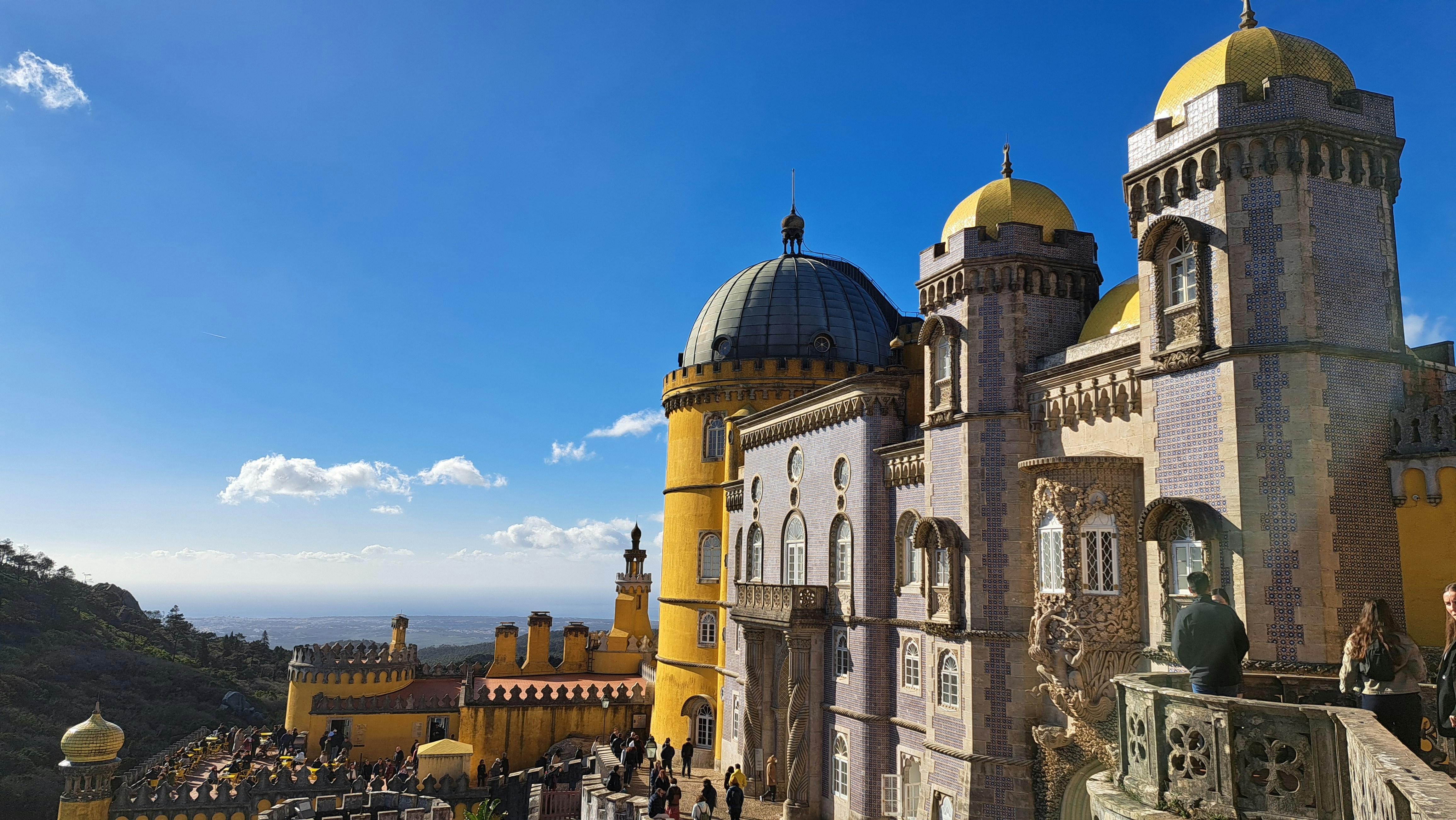 Colorful turrets of a historic palace under a clear blue sky in Sintra, Portugal.