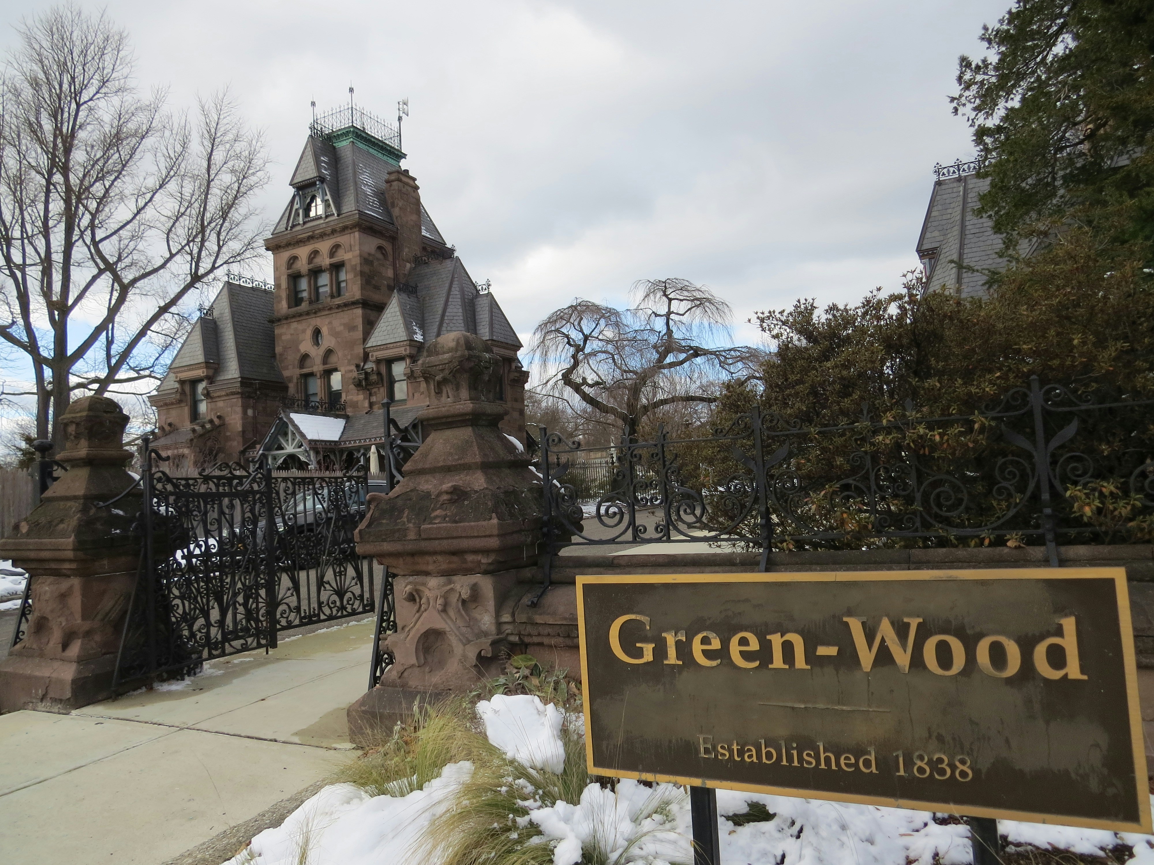Snowy Gatehouse at Green-Wood: A Timeless Welcome by the Iron Fence