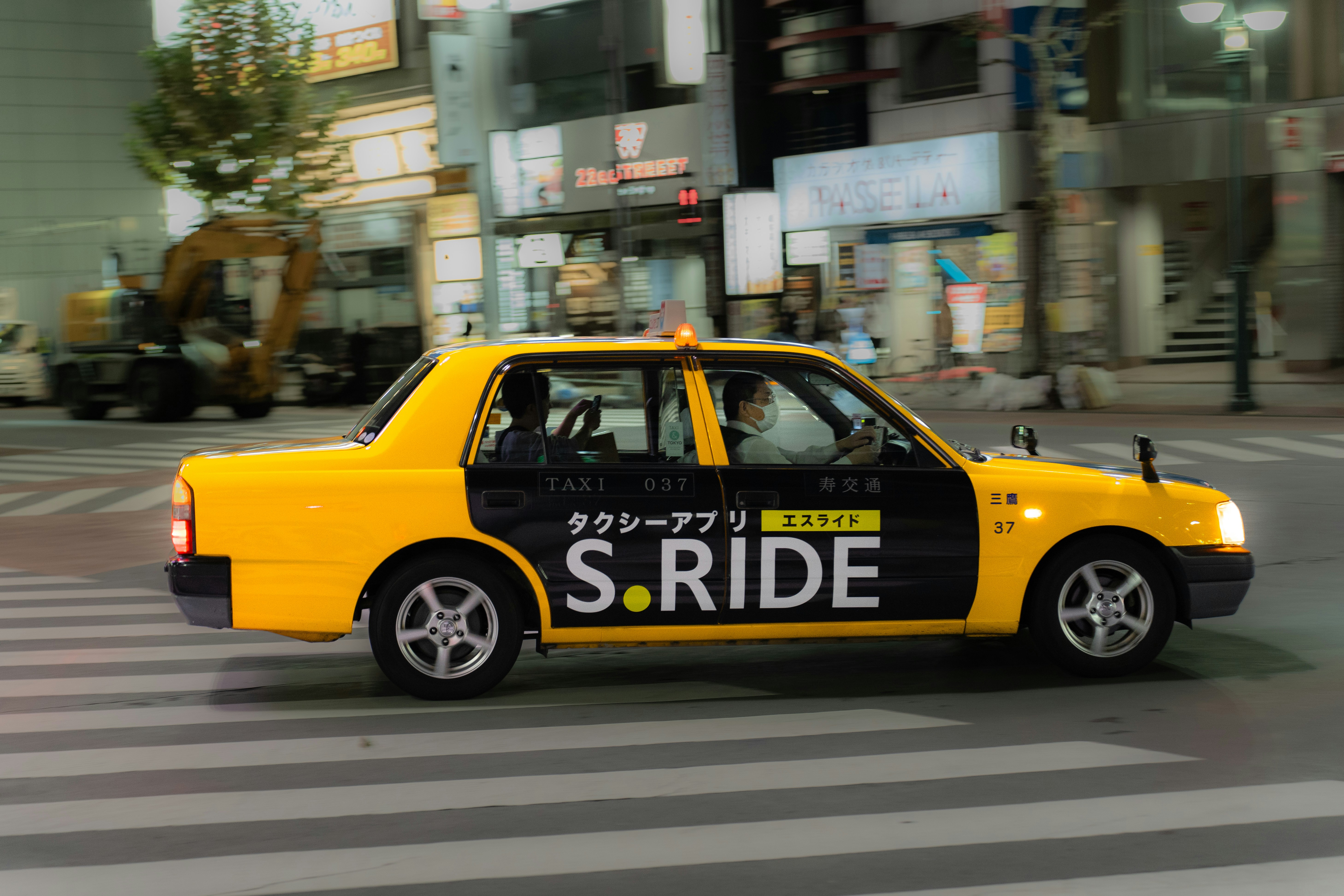 A taxi cab driving down a street next to tall buildings photo – Free ...